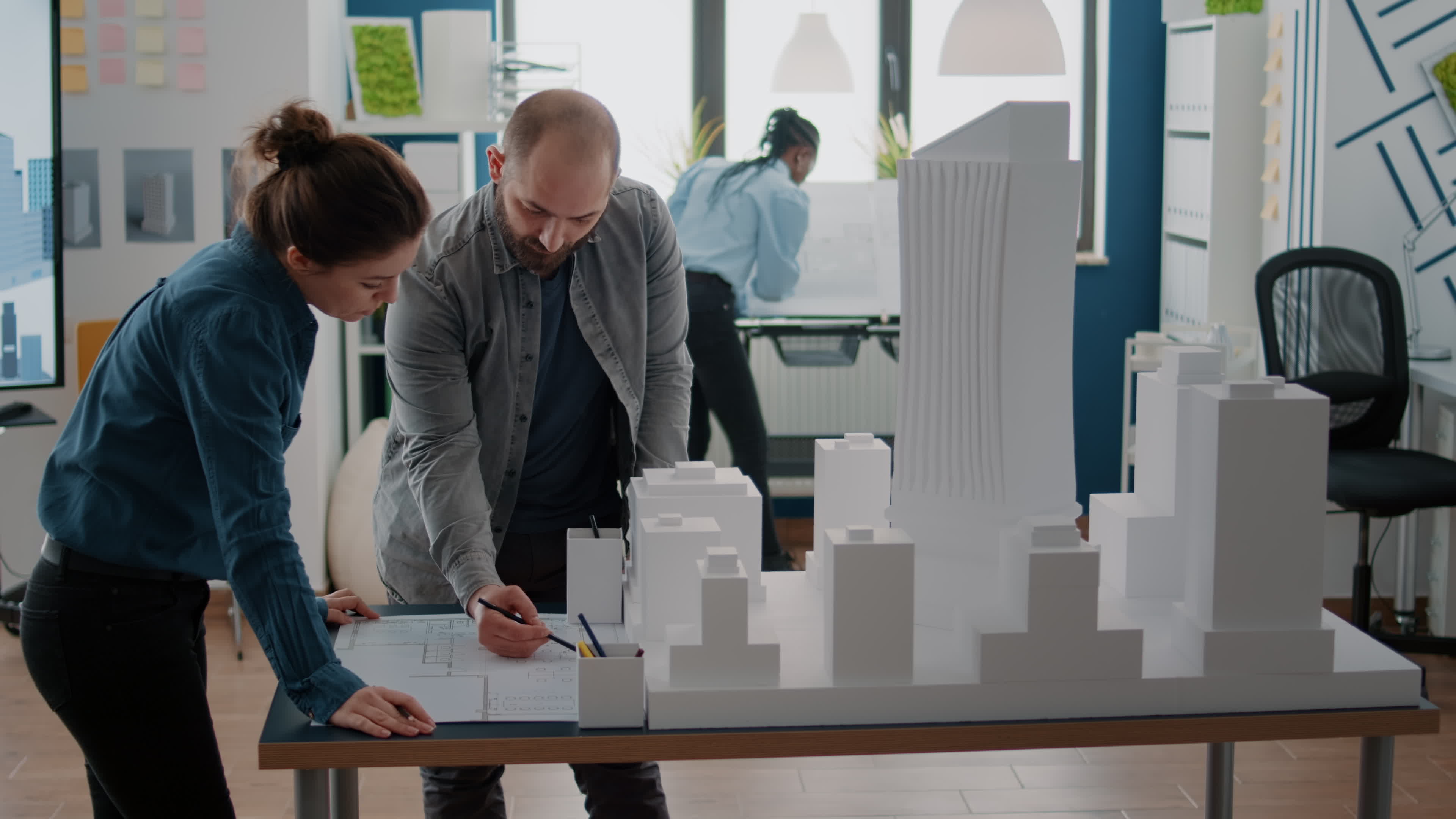 Workmates Analyzing Maquette And Blueprints Plan On Table To Work On Architecture And Building