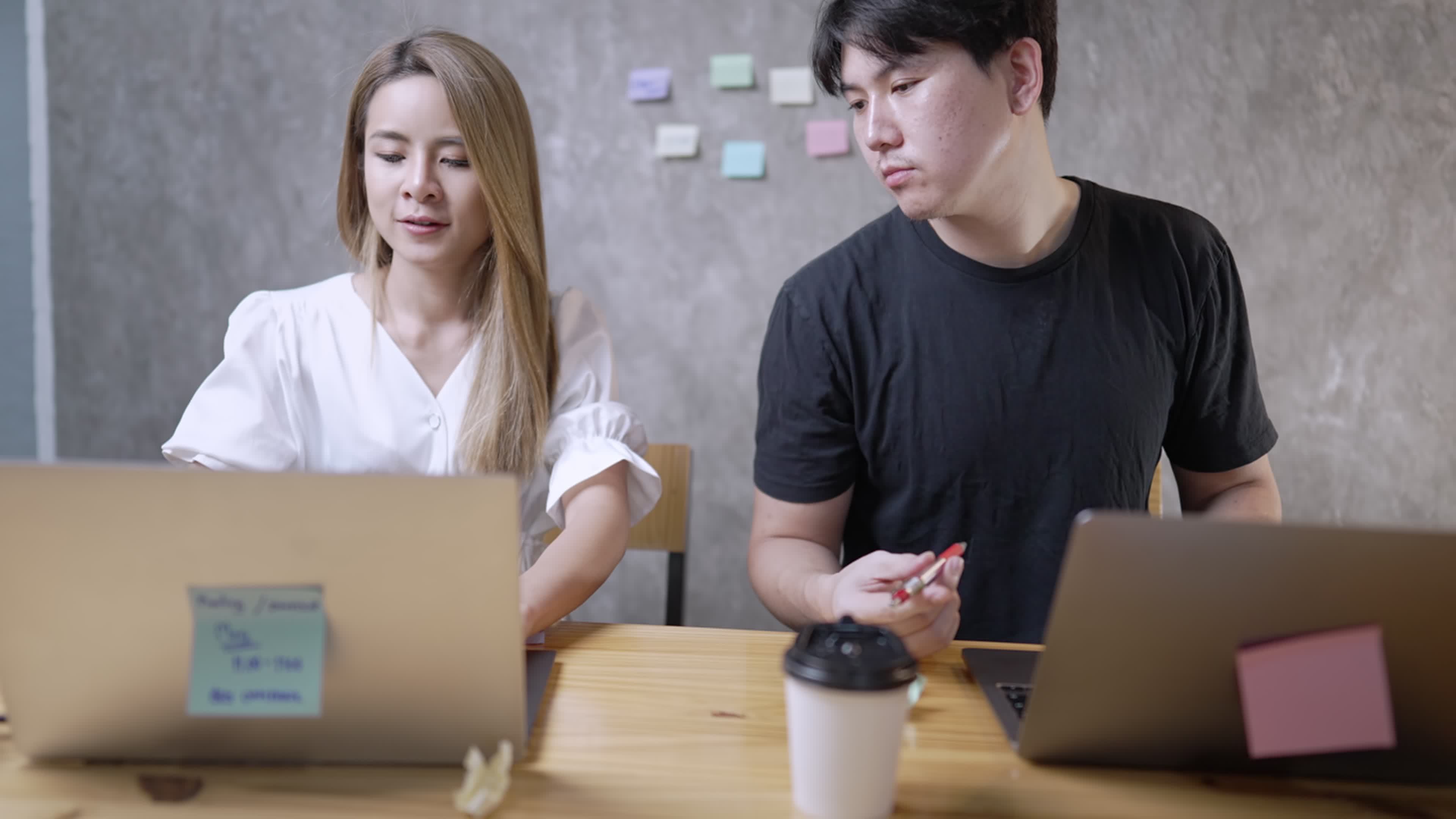 Young Handsome Man Spying On Female Colleague Who Is Working At Laptop