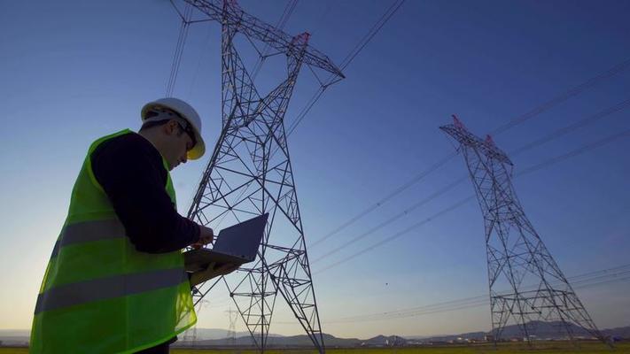 Electrical Energy and engineer. Engineer working on laptop in front of electric poles. Conducting field investigations. Electrical engineer