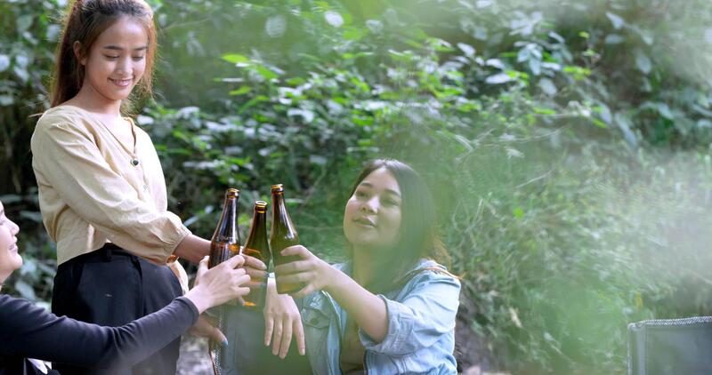 Handheld shot, Group beautiful Asian women friends travelers relaxing in camp chairs in stream ...