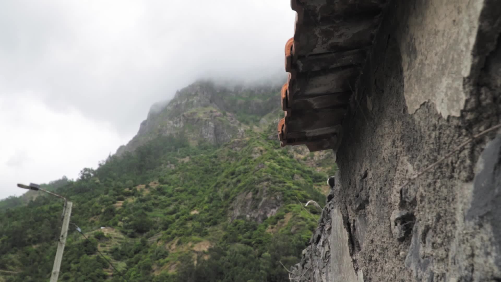 Close up of old stone building side and roof with foggy mountain ... Close up of old stone building side and roof with foggy mountain ...