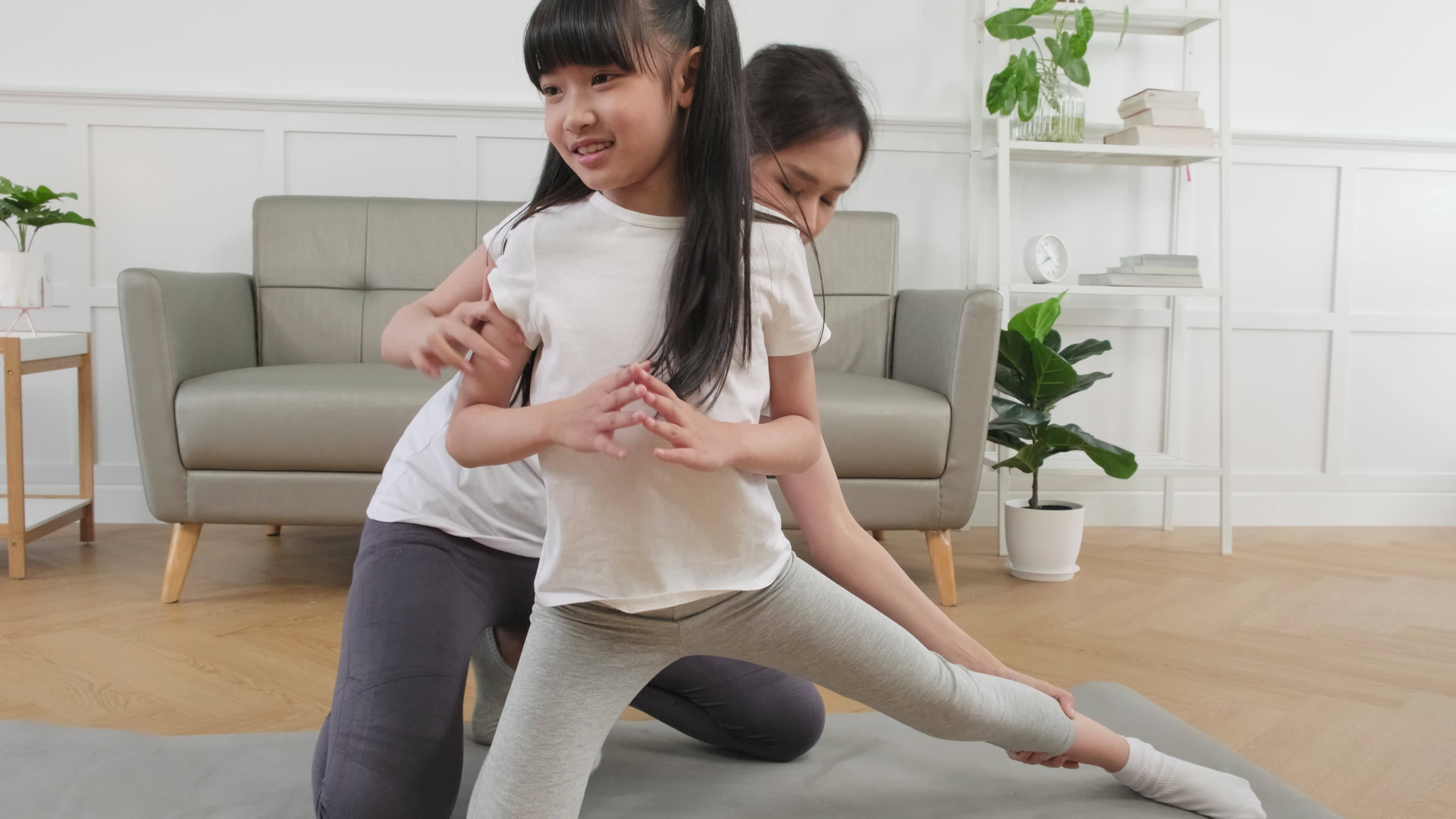 Young Asian Thai mother lovely trains her little daughter to exercise and practices yoga on ...