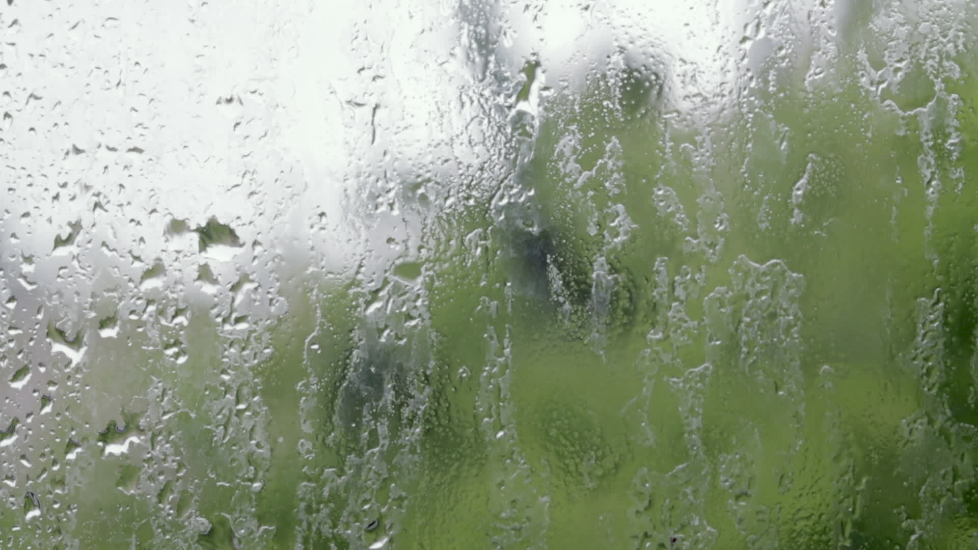 Heavy rain. Raindrops on the window glass on a summer day. Selective focus, shallow depth of ...