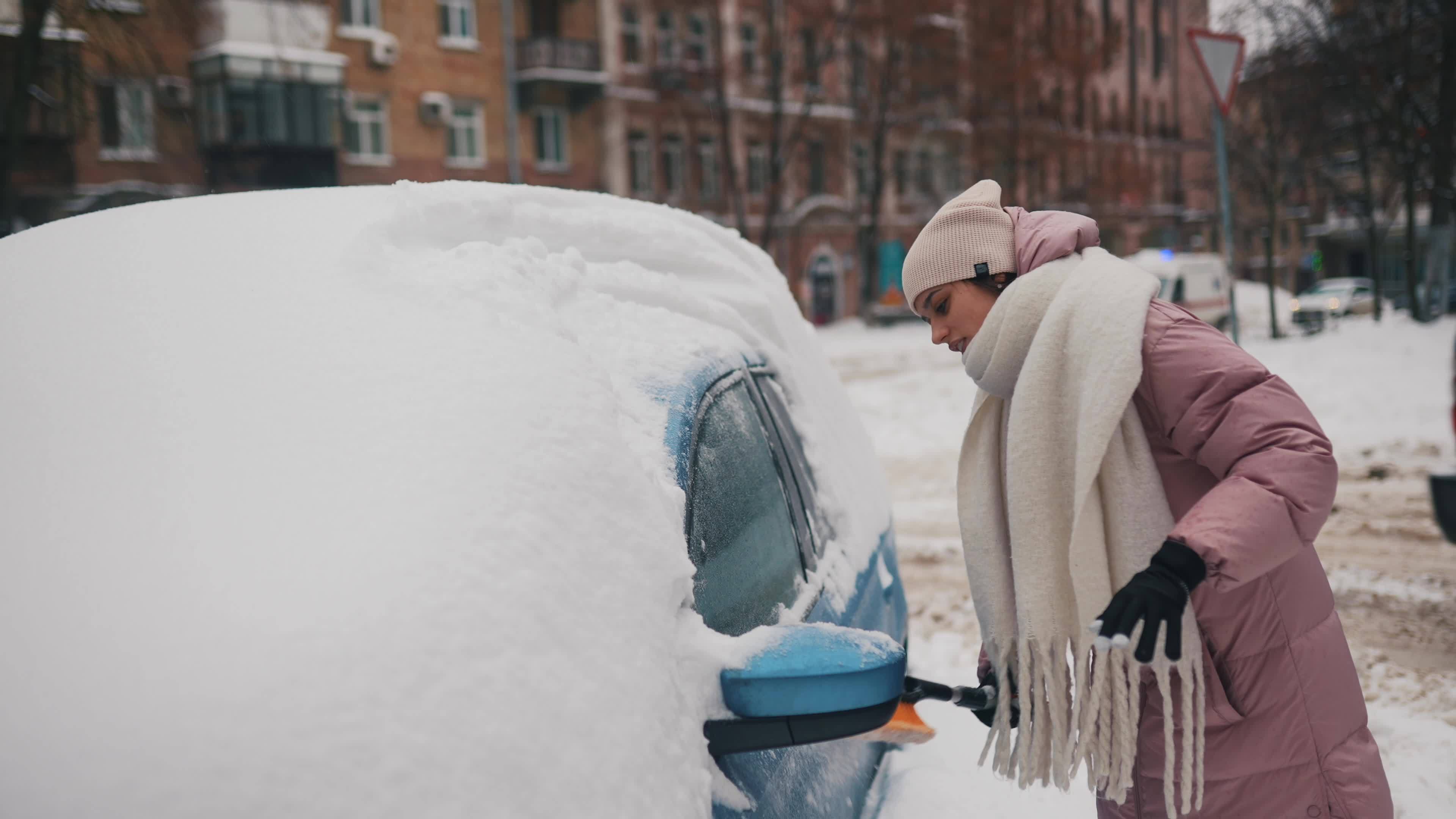 Young woman in pink puffy coat brushes snow off car 11698782 Stock ...