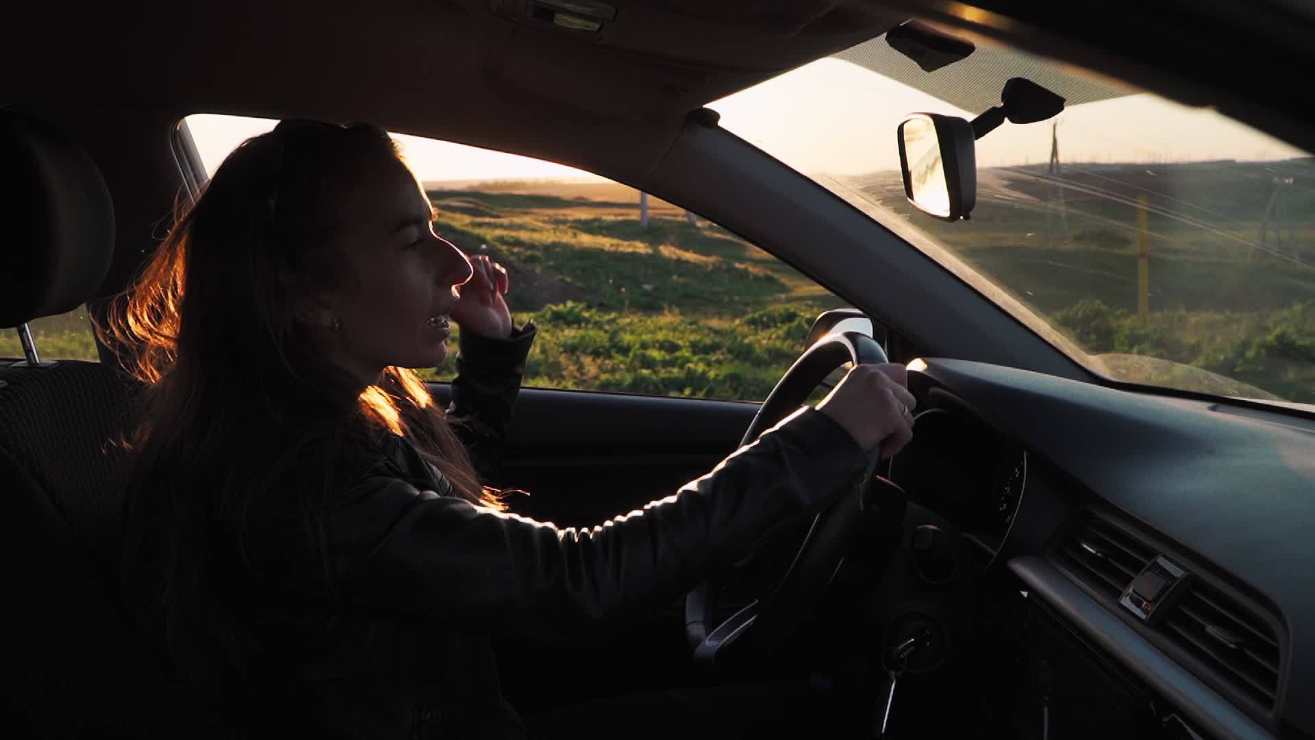 young woman driving the car outside the window beautiful sunset ...