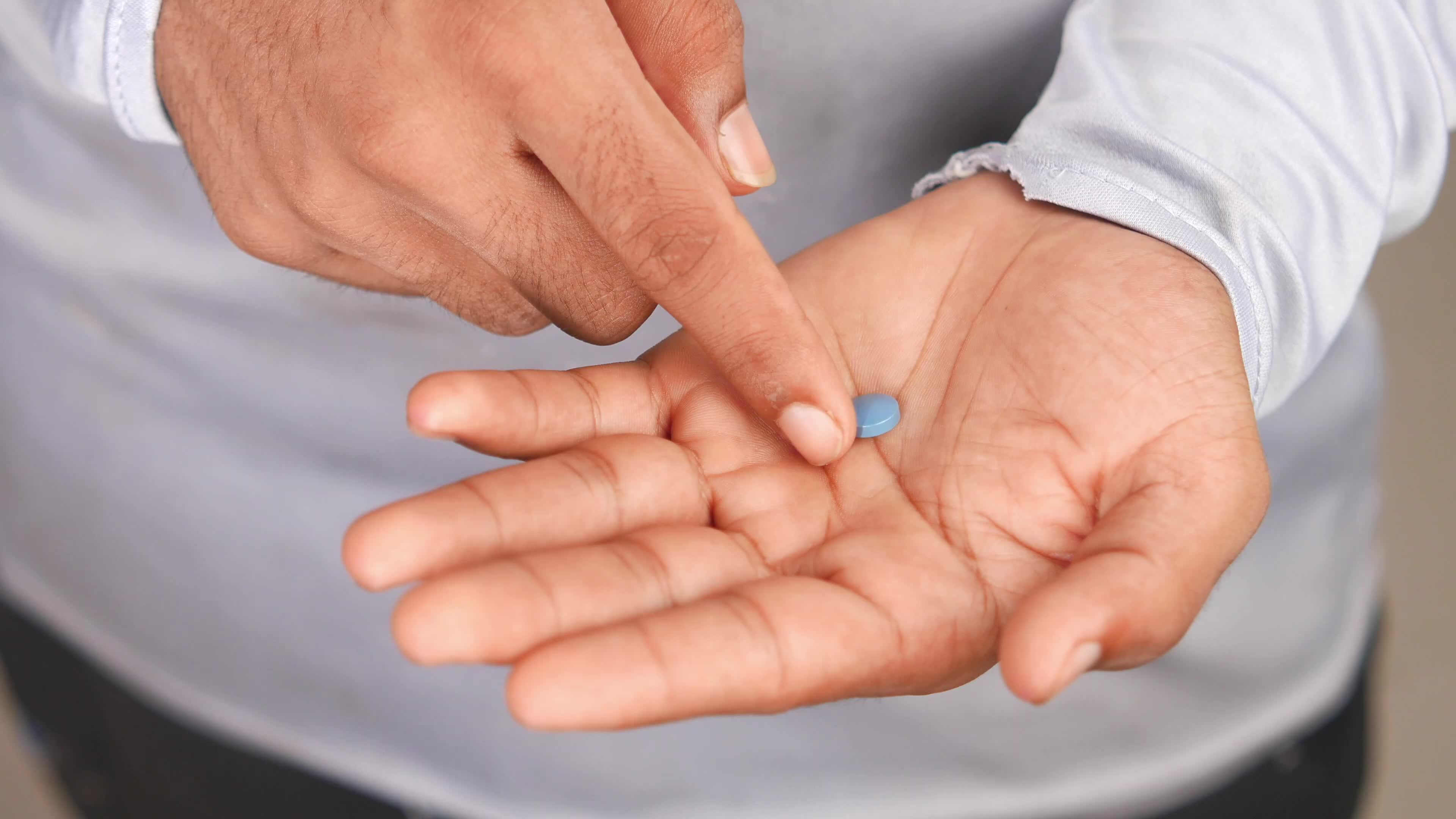 Man have a little blue pill in hand 14005357 Stock Video at Vecteezy