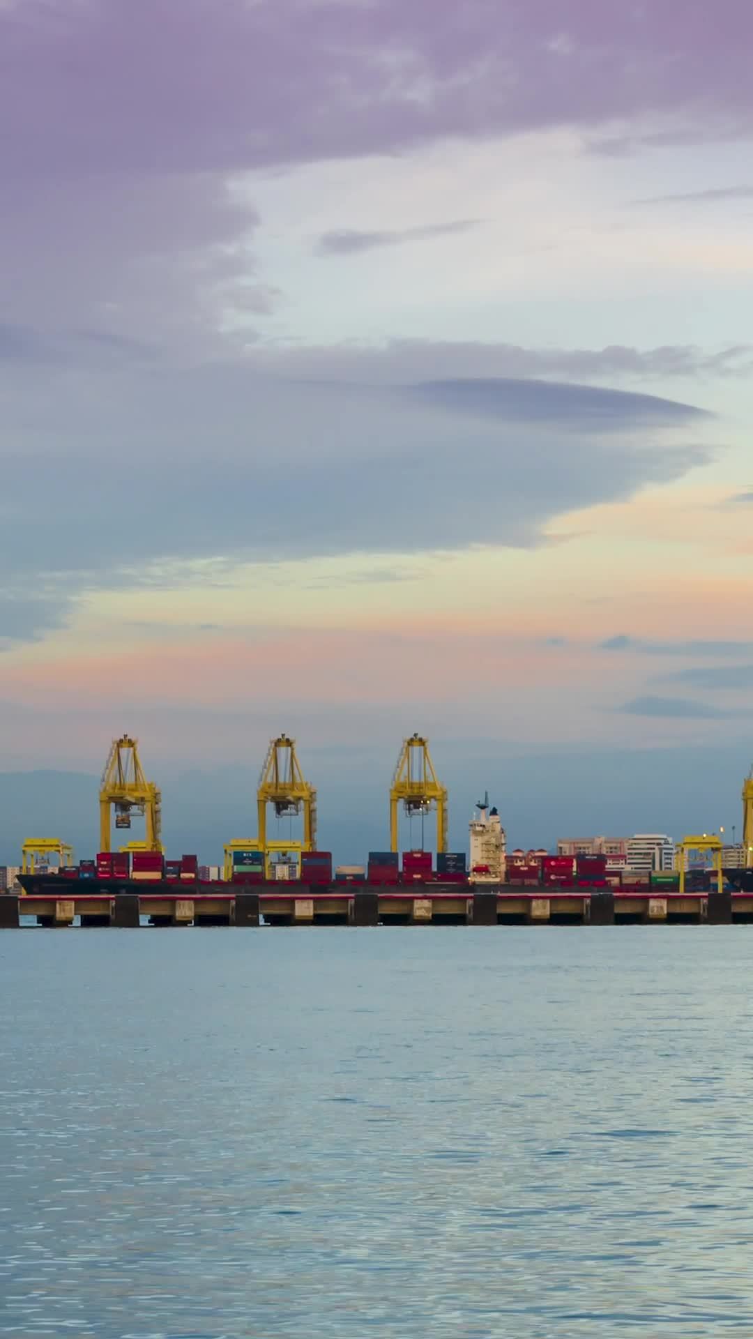 vertical timelapse of deep sea port with cargoship loading and ...
