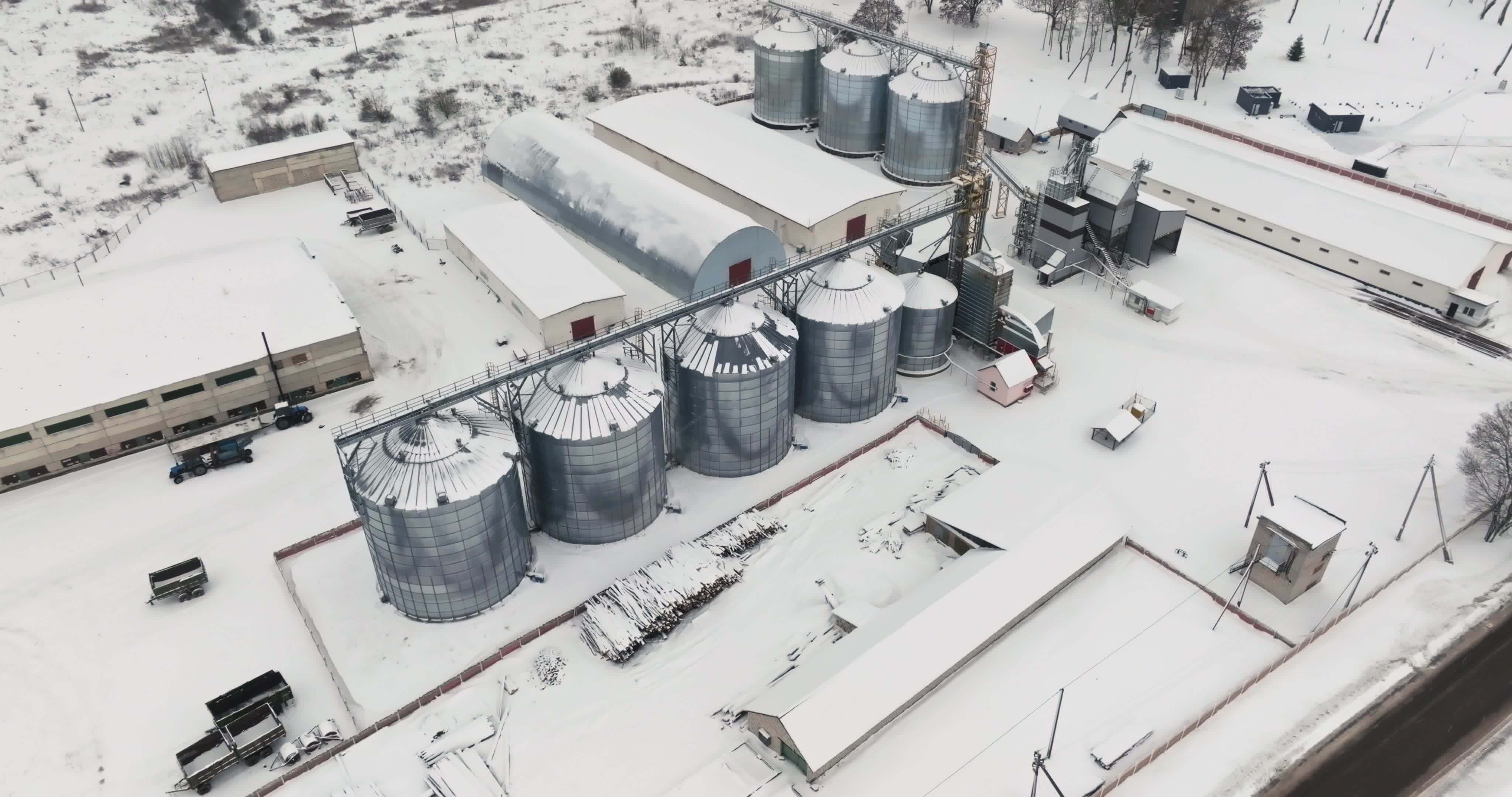 flight over agro silos granary elevator in winter day in snowy field ...
