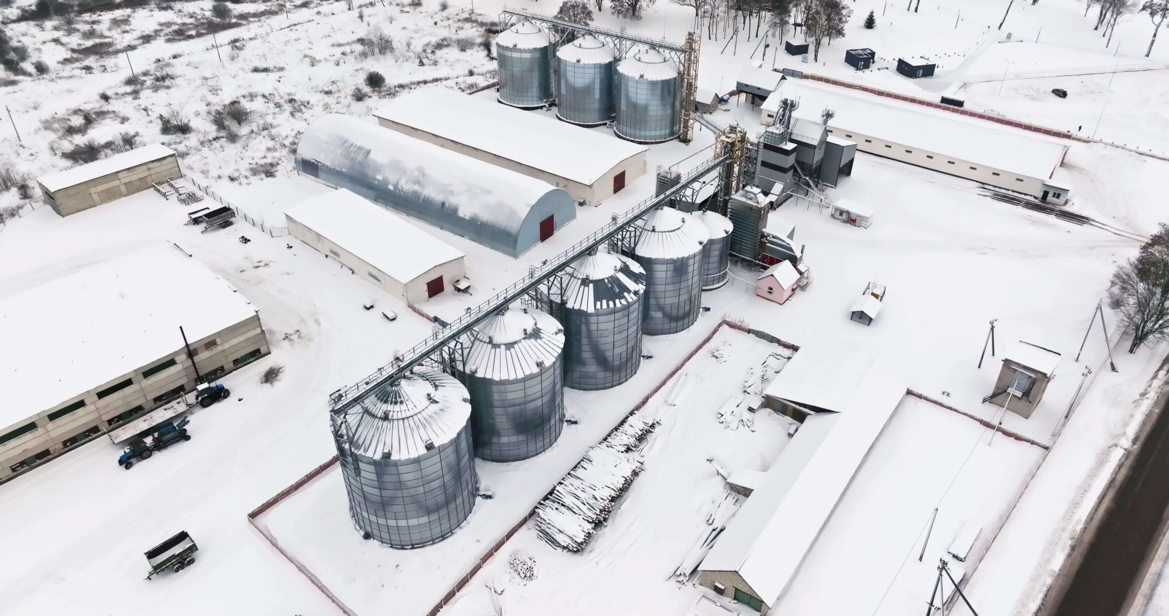 flight over agro silos granary elevator in winter day in snowy field ...