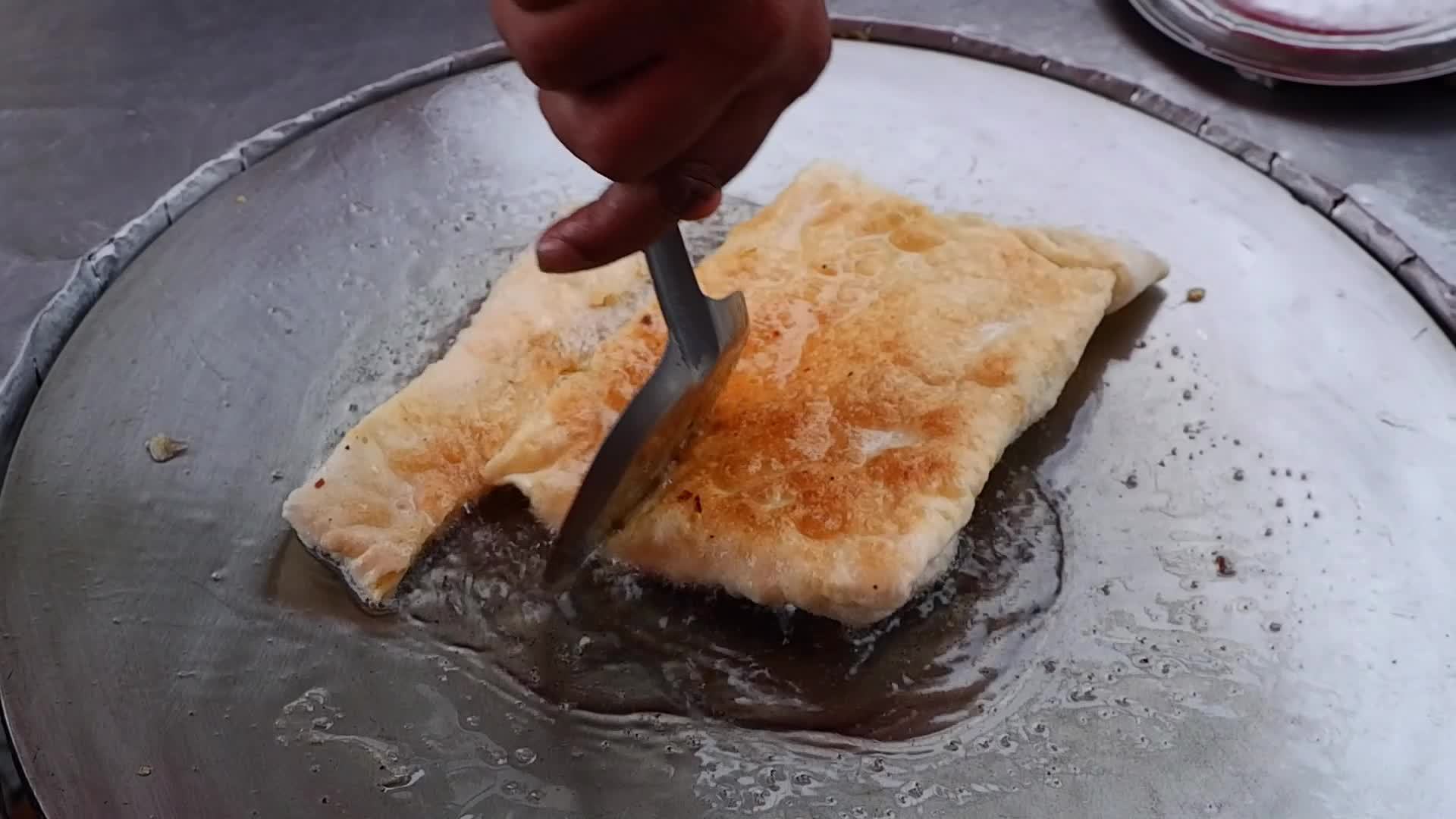 street food in thailand Crispy flour roti on a large flat pan The chef is frying the roti dough ...