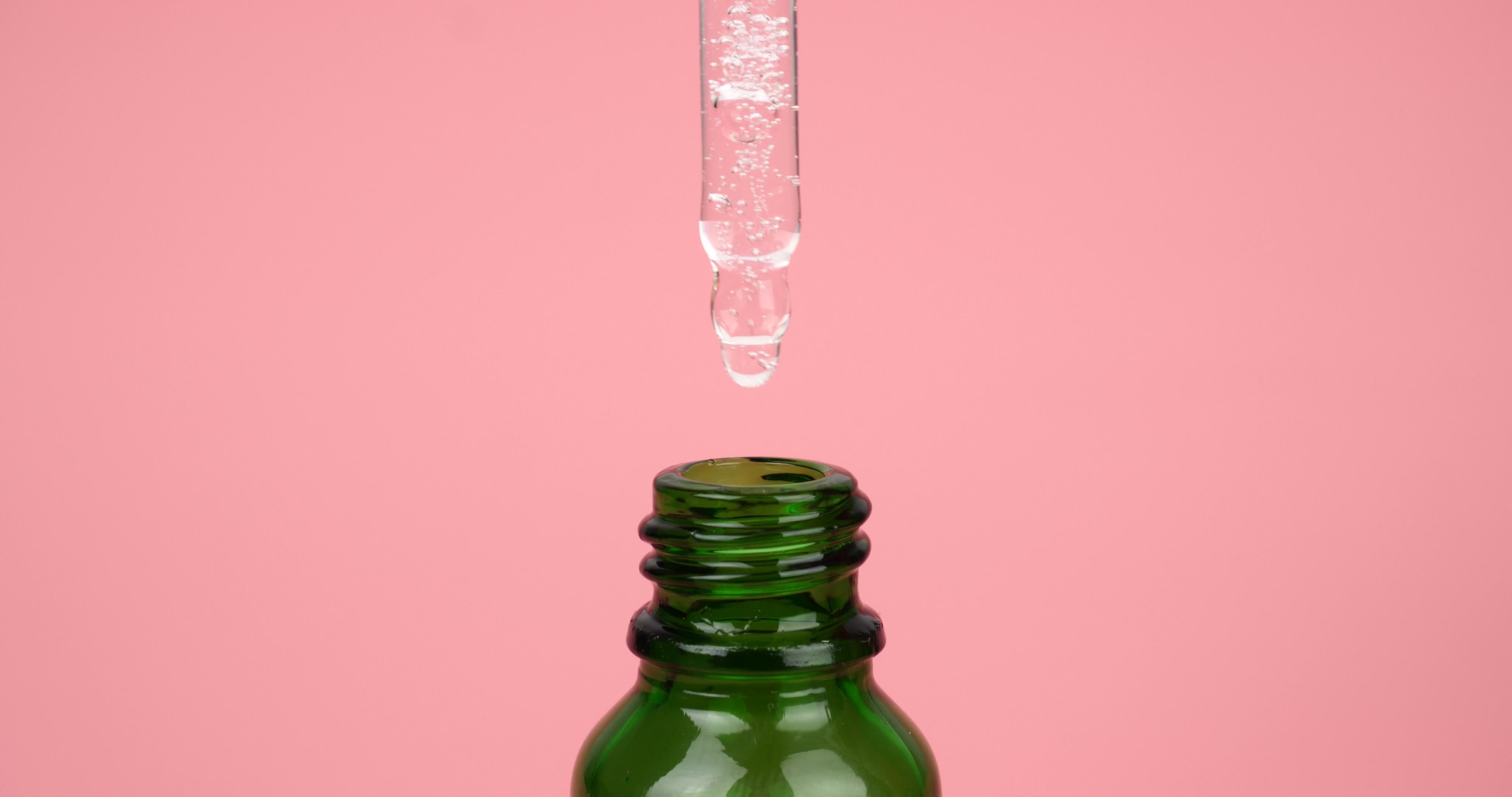 pipette and bottle, drops of cosmetic extract on a pink background 16364715 Stock Video at Vecteezy