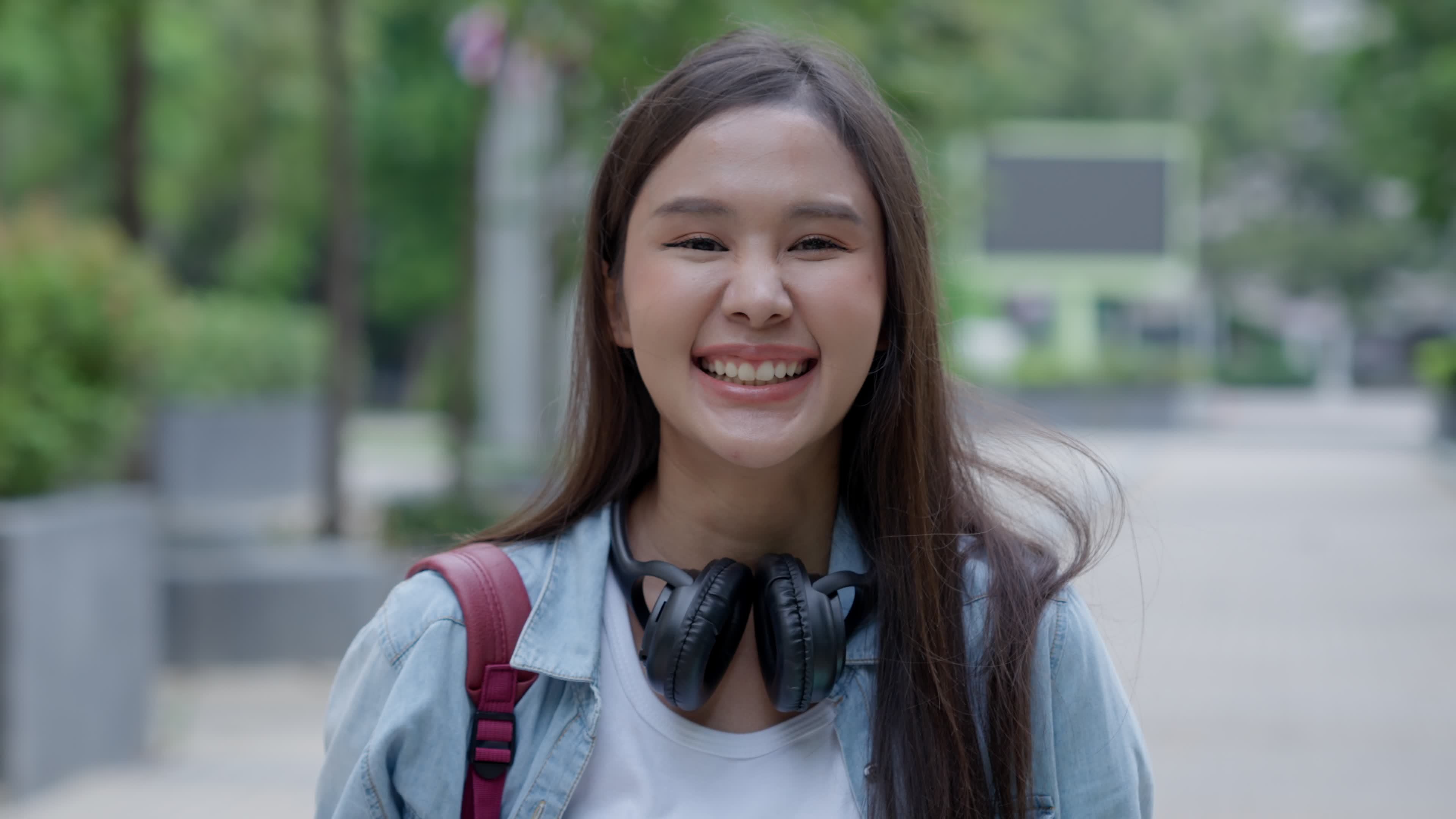 Beautiful student asian woman with backpack and books outdoor. Smile girl happy carrying a lot ...