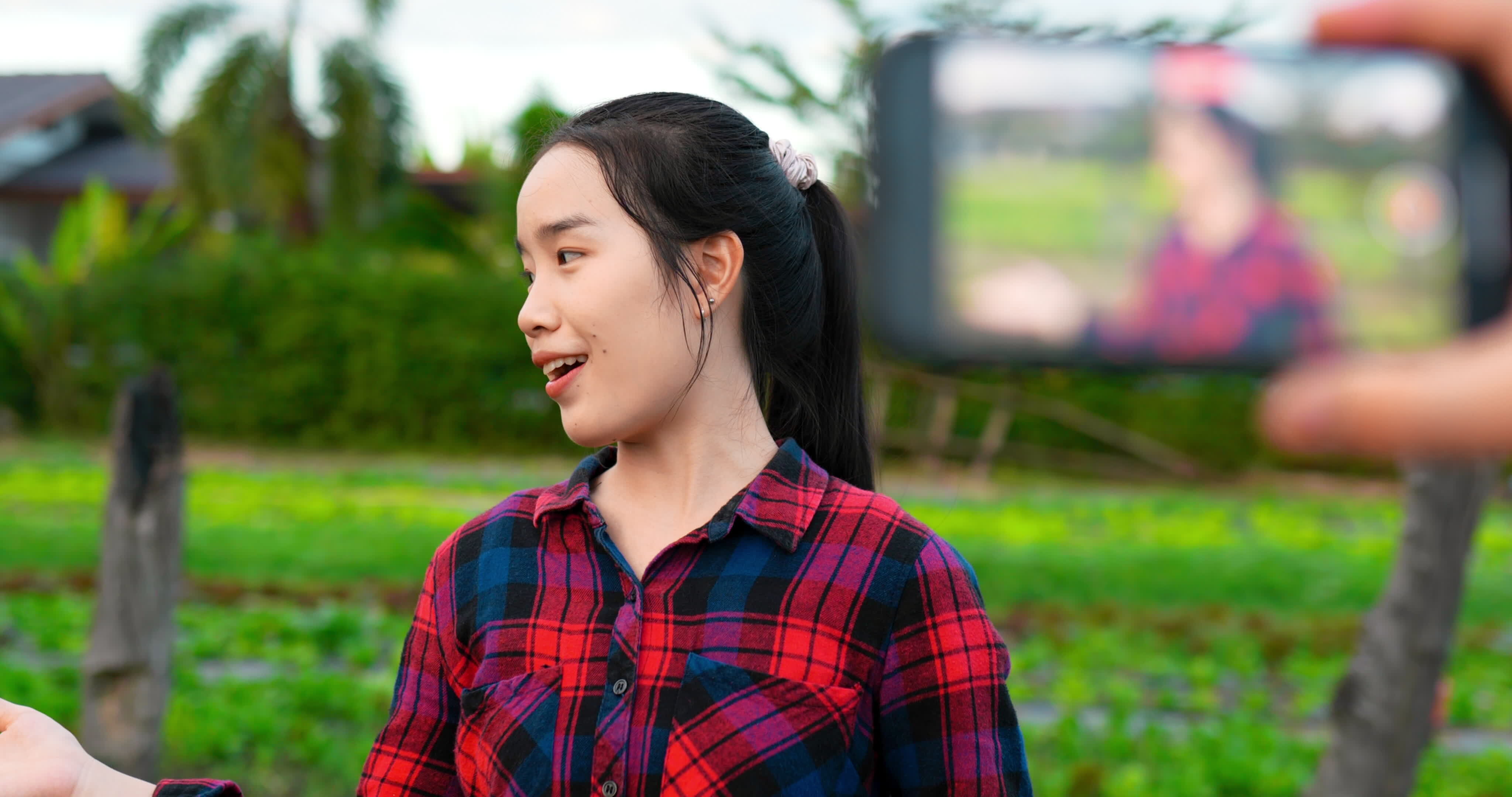 toma de mano, una agricultora usa un pantalones a cuadros hablando en un teléfono inteligente y ...
