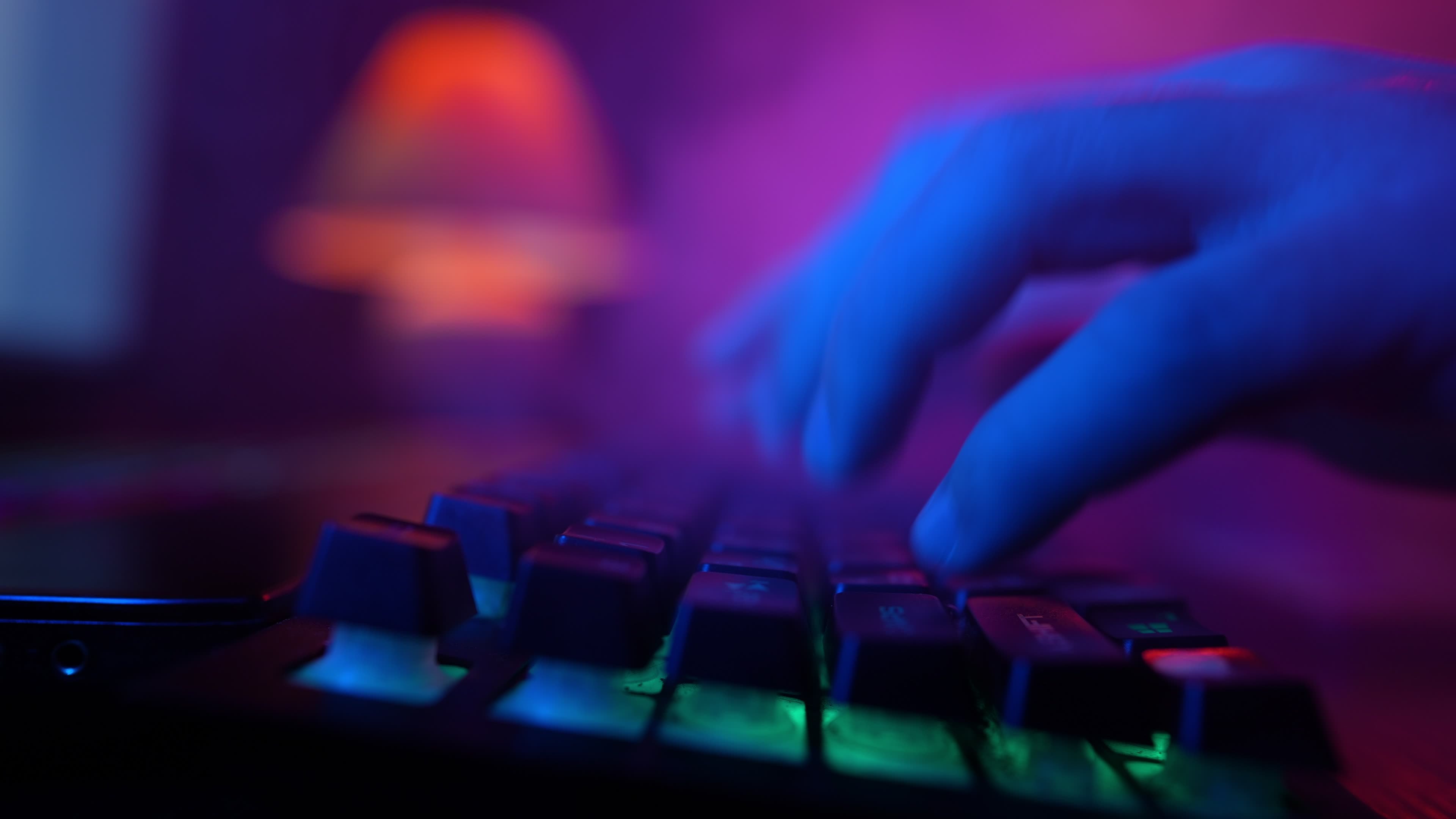 Close Up Unrecognizable Man Using A Computer Keyboard To Code A Website In Neon Lighting