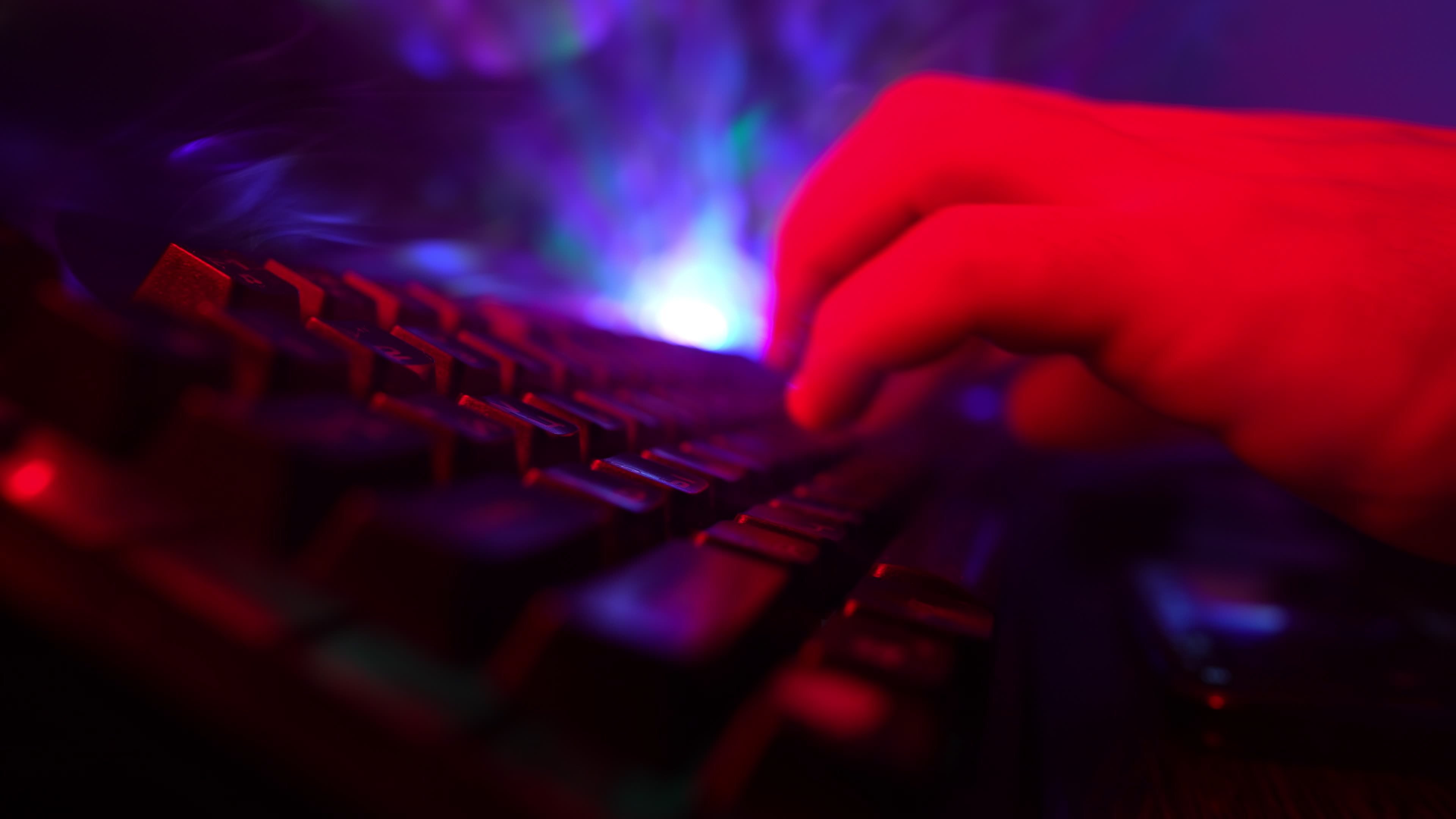 Close Up Unrecognizable Man Using A Computer Keyboard To Code A Website In Neon Lighting