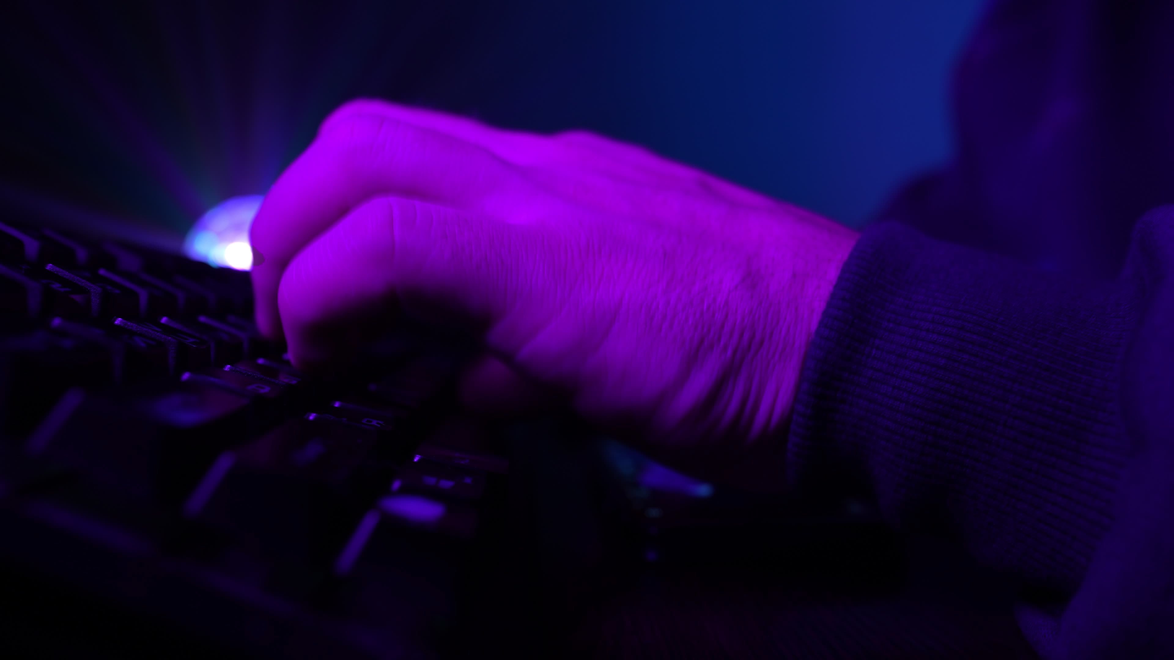 Close Up Unrecognizable Man Using A Computer Keyboard To Code A Website In Neon Lighting