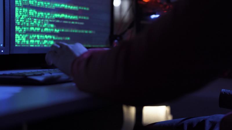 Lonely hacker programmer surrounded by programming codes interface in a dark environment ...