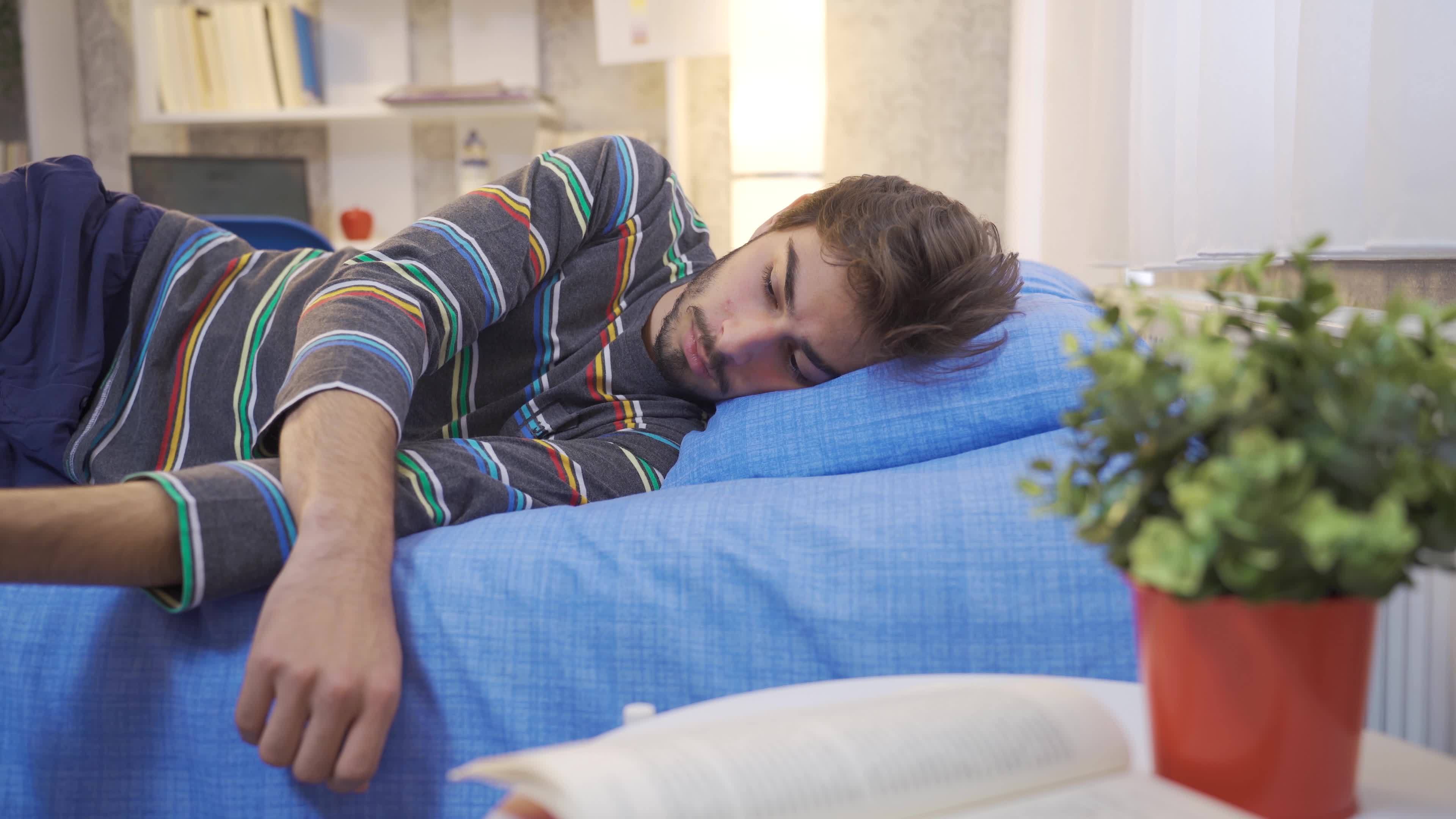 The young man lying in his bed is thoughtful. Young man with anxiety ...