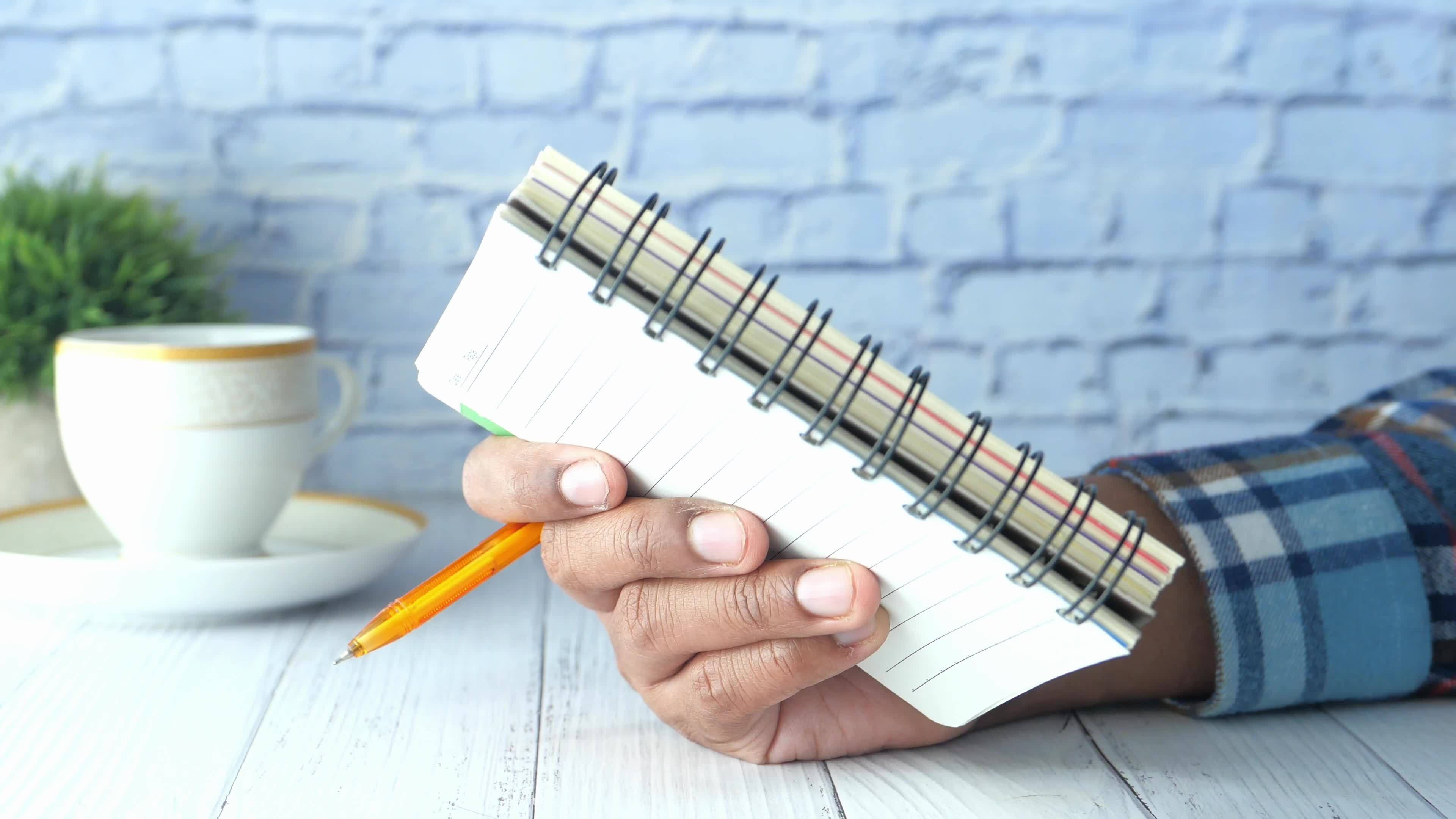 Man hand writing on notepad while seated 21721491 Stock Video at Vecteezy