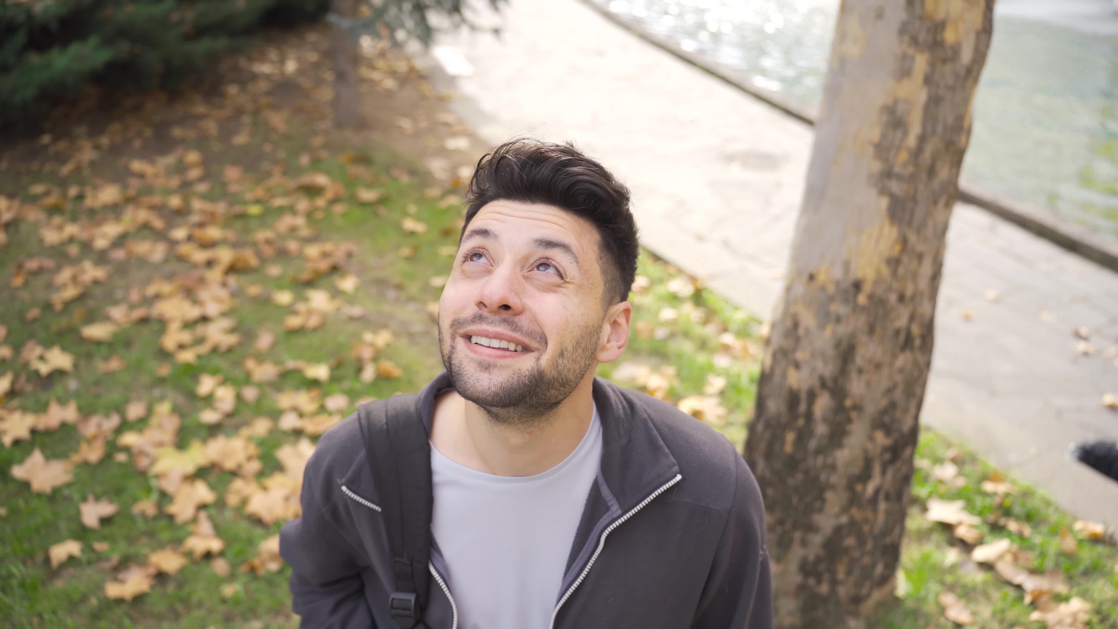 Outdoors portrait of young man looking at the sky. Close-up portrait of ...