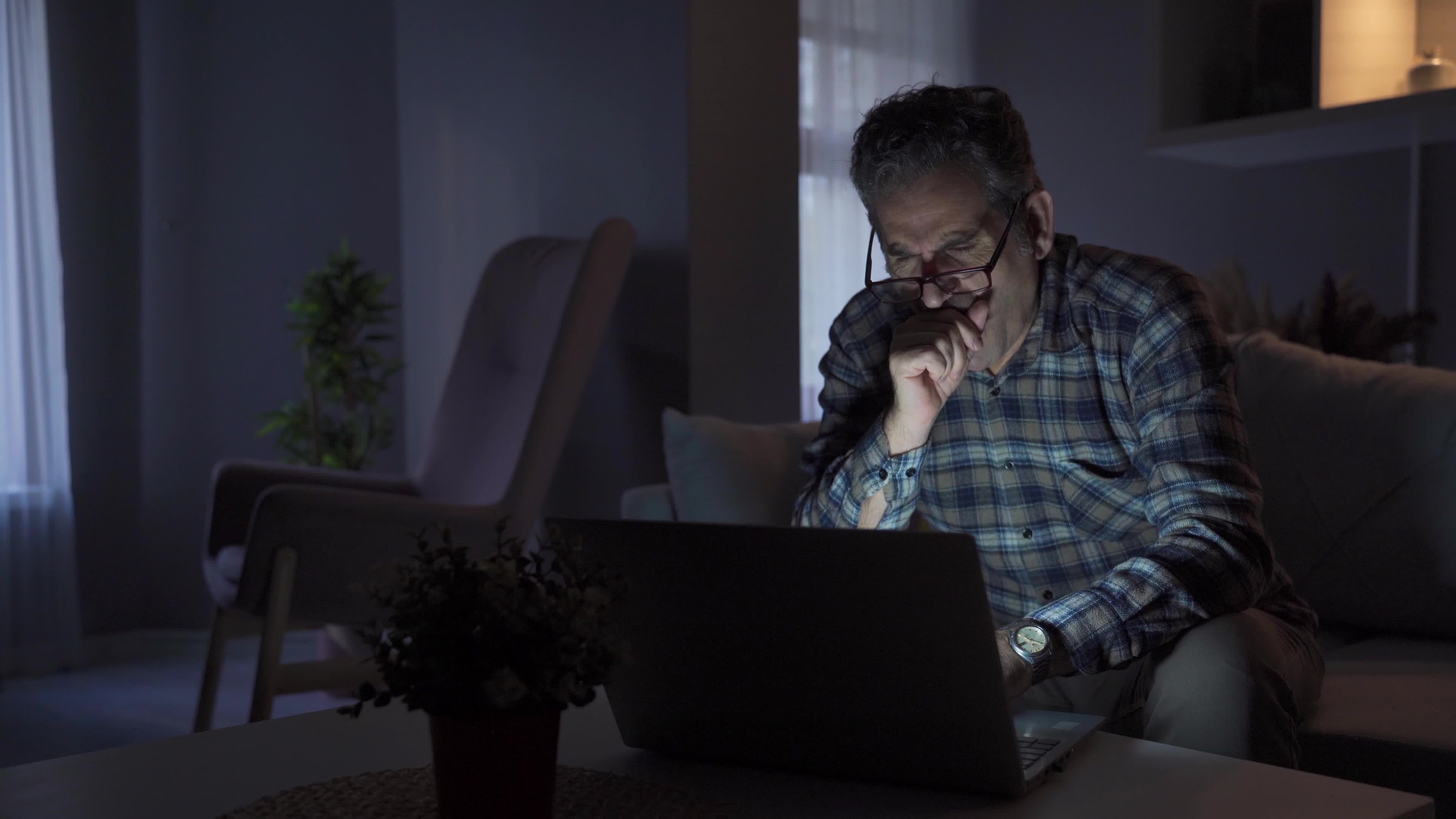 Mature man has sore eyes and sleepiness from working on laptop at night ...