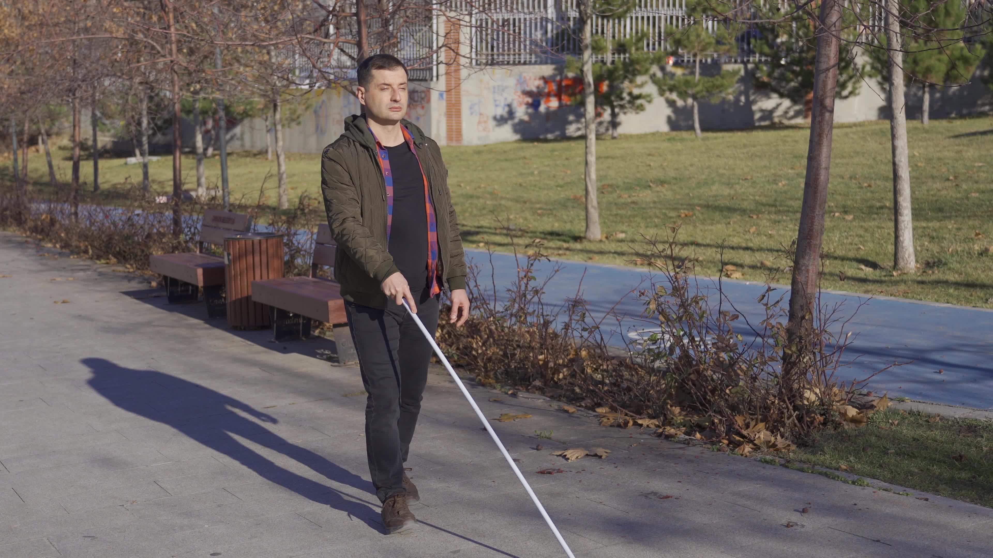 The blind man walks alone on the road. He has a walking stick. In ... The blind man walks alone on the road. He has a walking stick. In ...