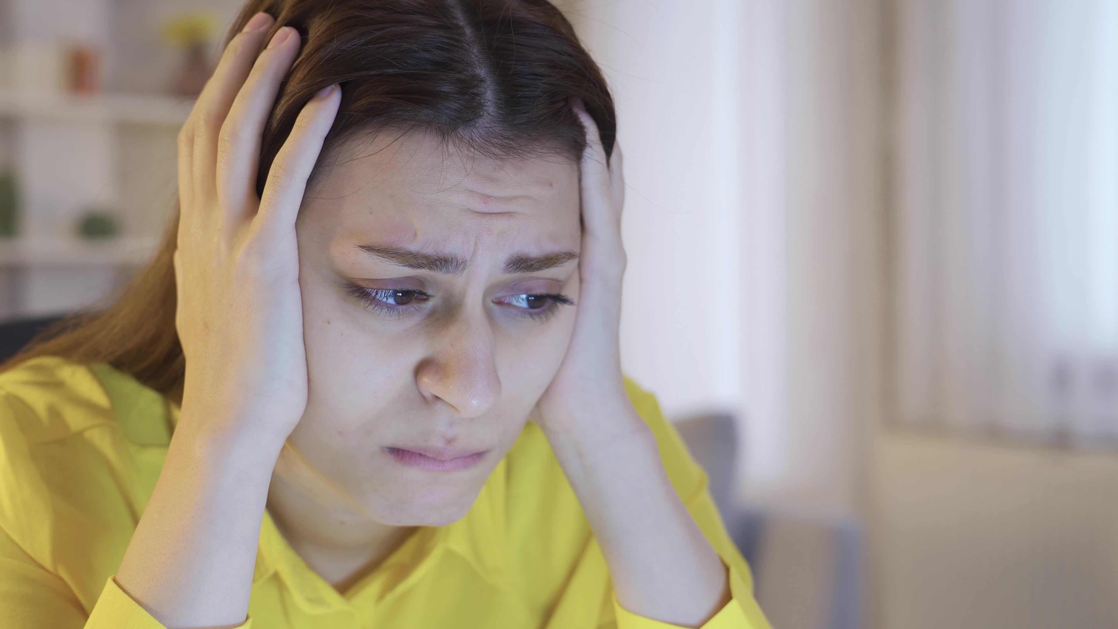 Sad and worried young woman looking at laptop at home and feeling ...