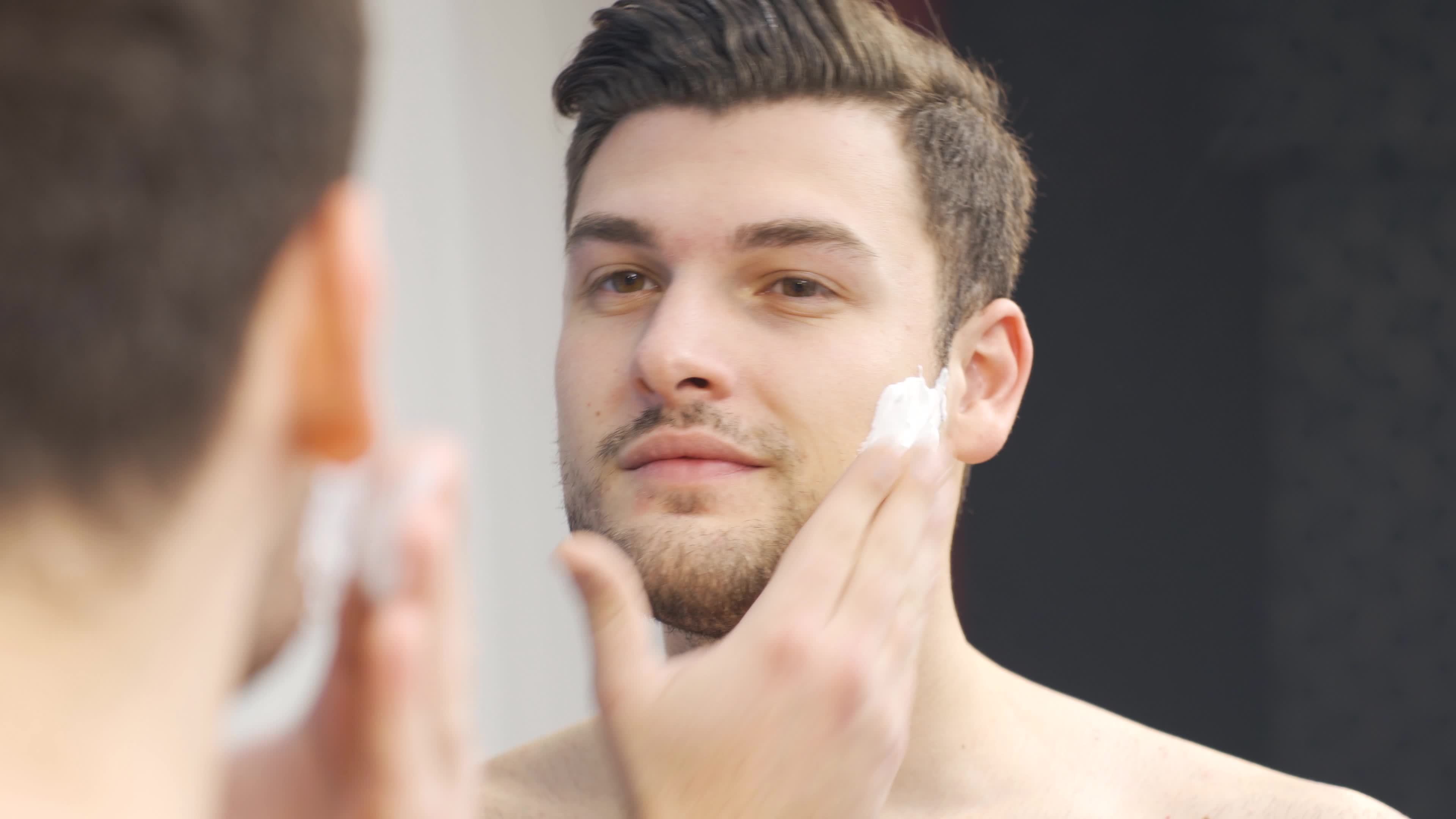 Handsome man applying shaving foam to his beard to shave. Young man ... Handsome man applying shaving foam to his beard to shave. Young man ...