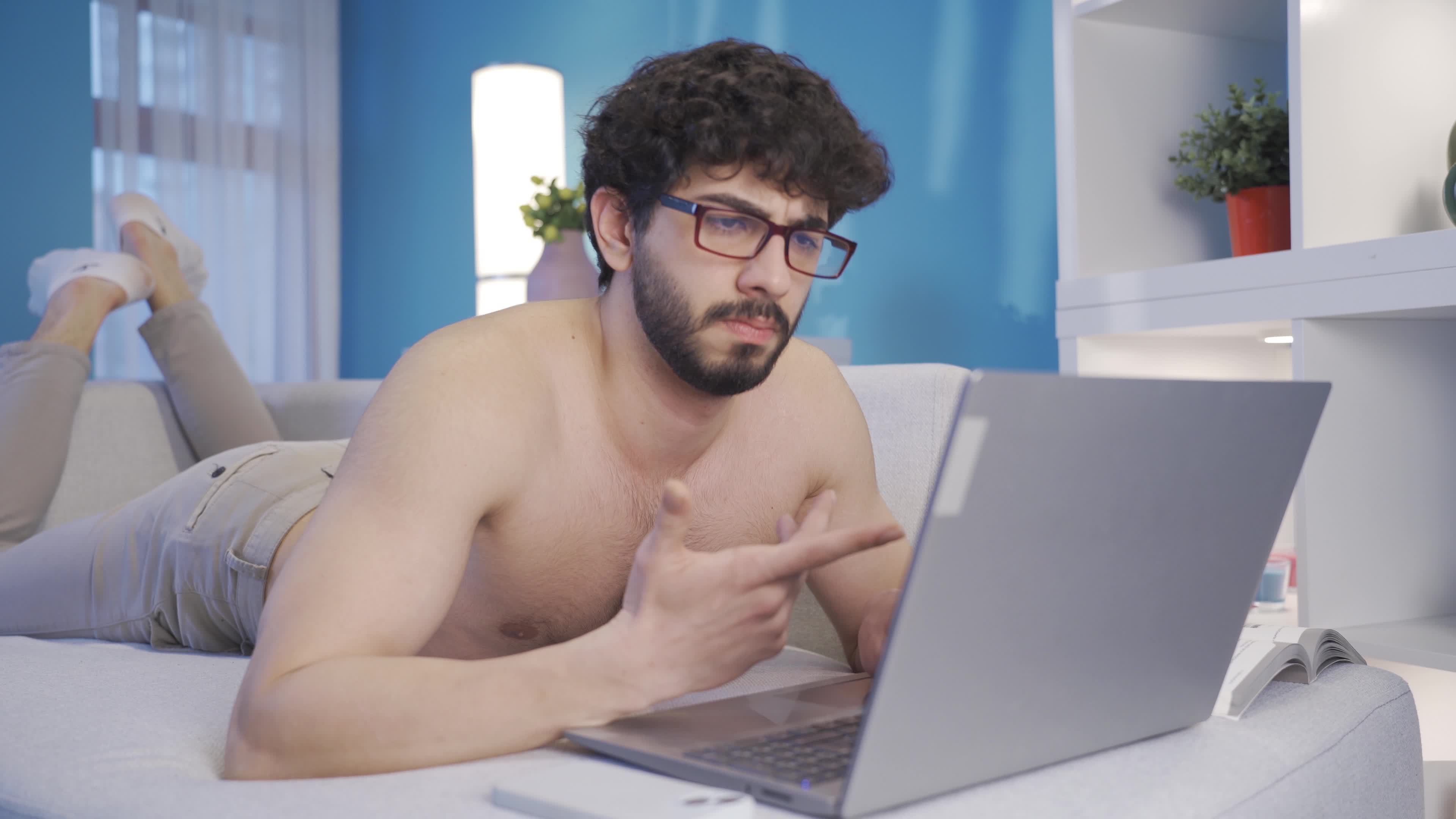 Successful and smart man using laptop naked at home, working. Naked young man doing business at ...