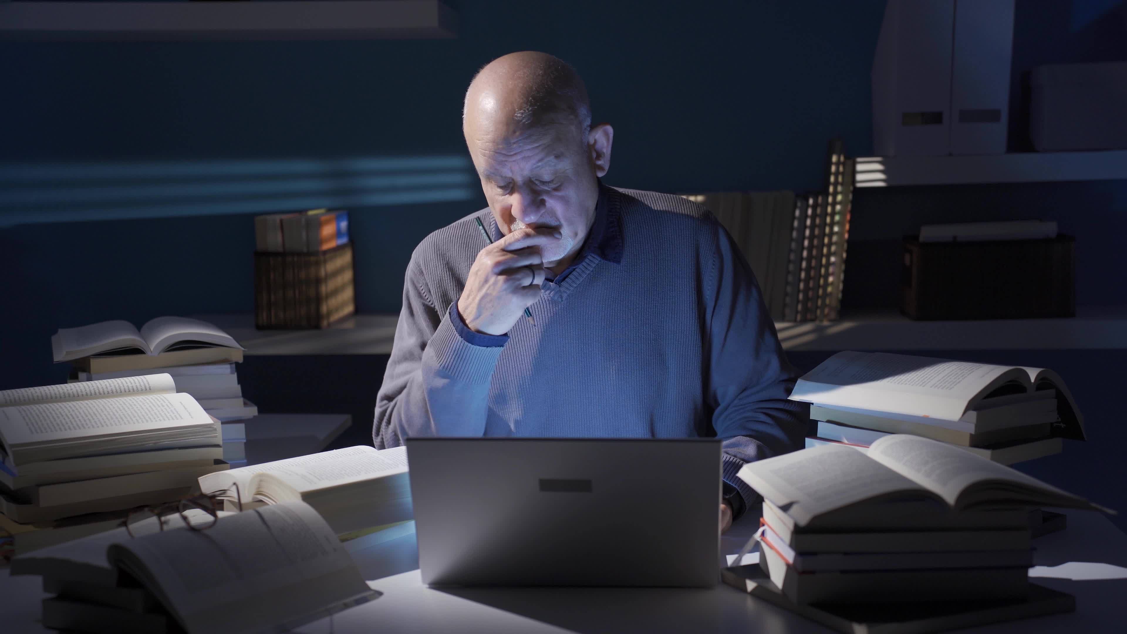 Researcher or historian old man working in dark room working on laptop ...