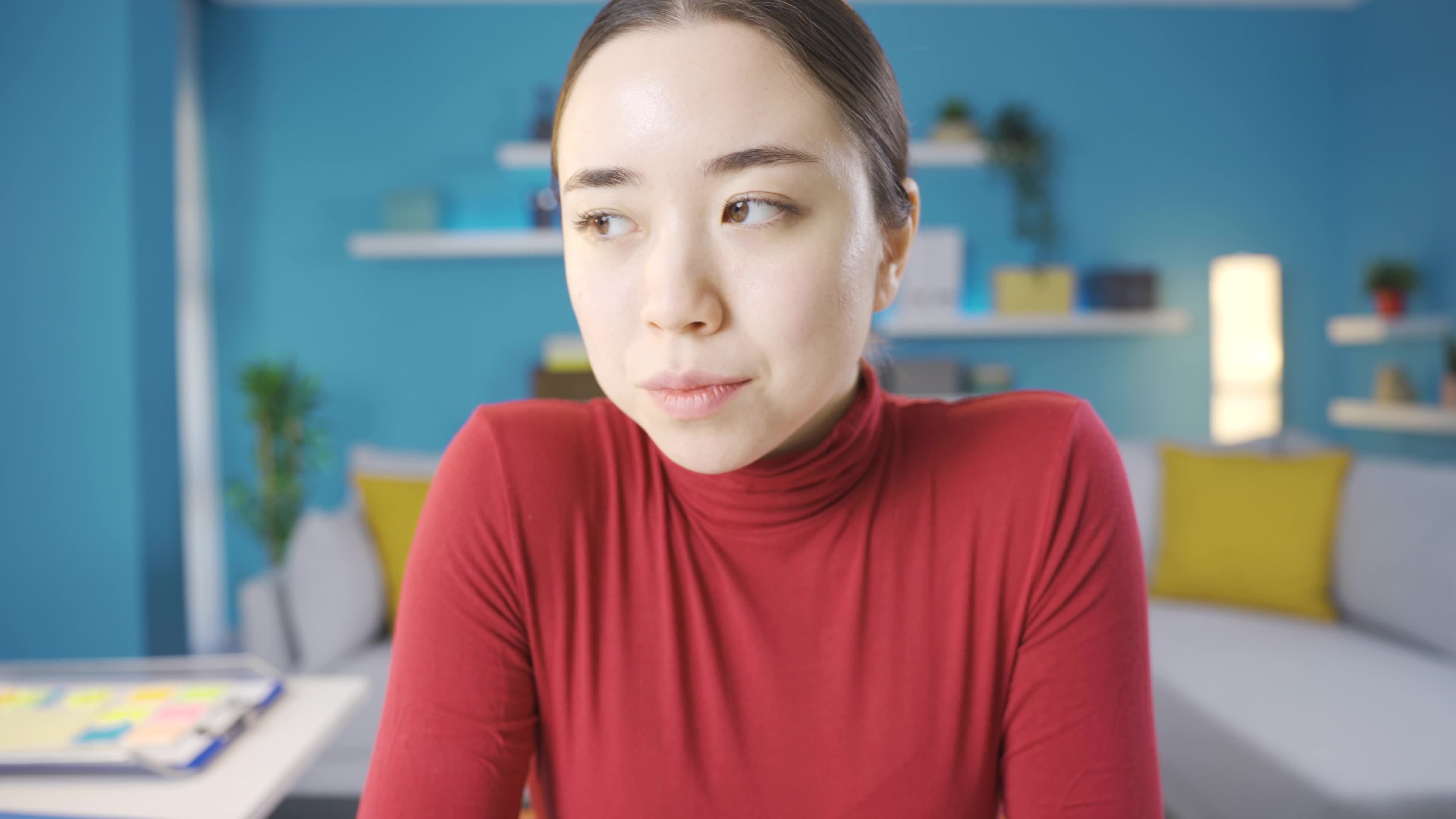 Asian woman thoughtfully looking around and at camera. Young Asian ...