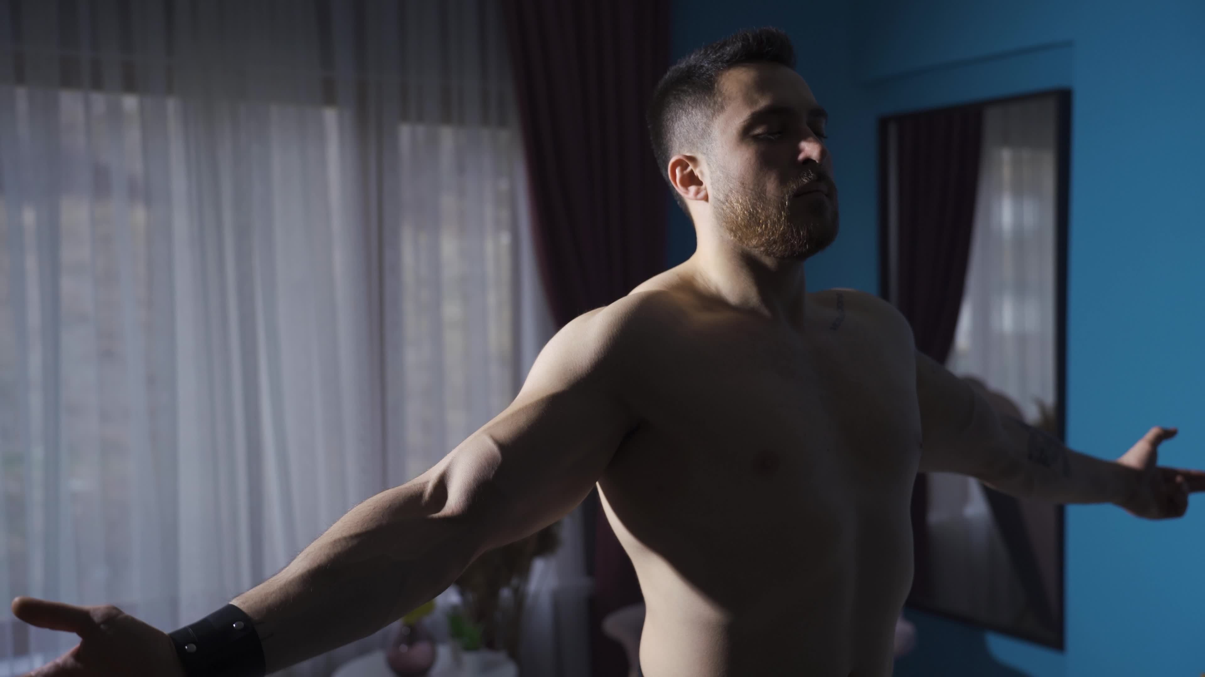 Young man with big and muscular body doing self pose at home. Young bodybuilder man at home ...