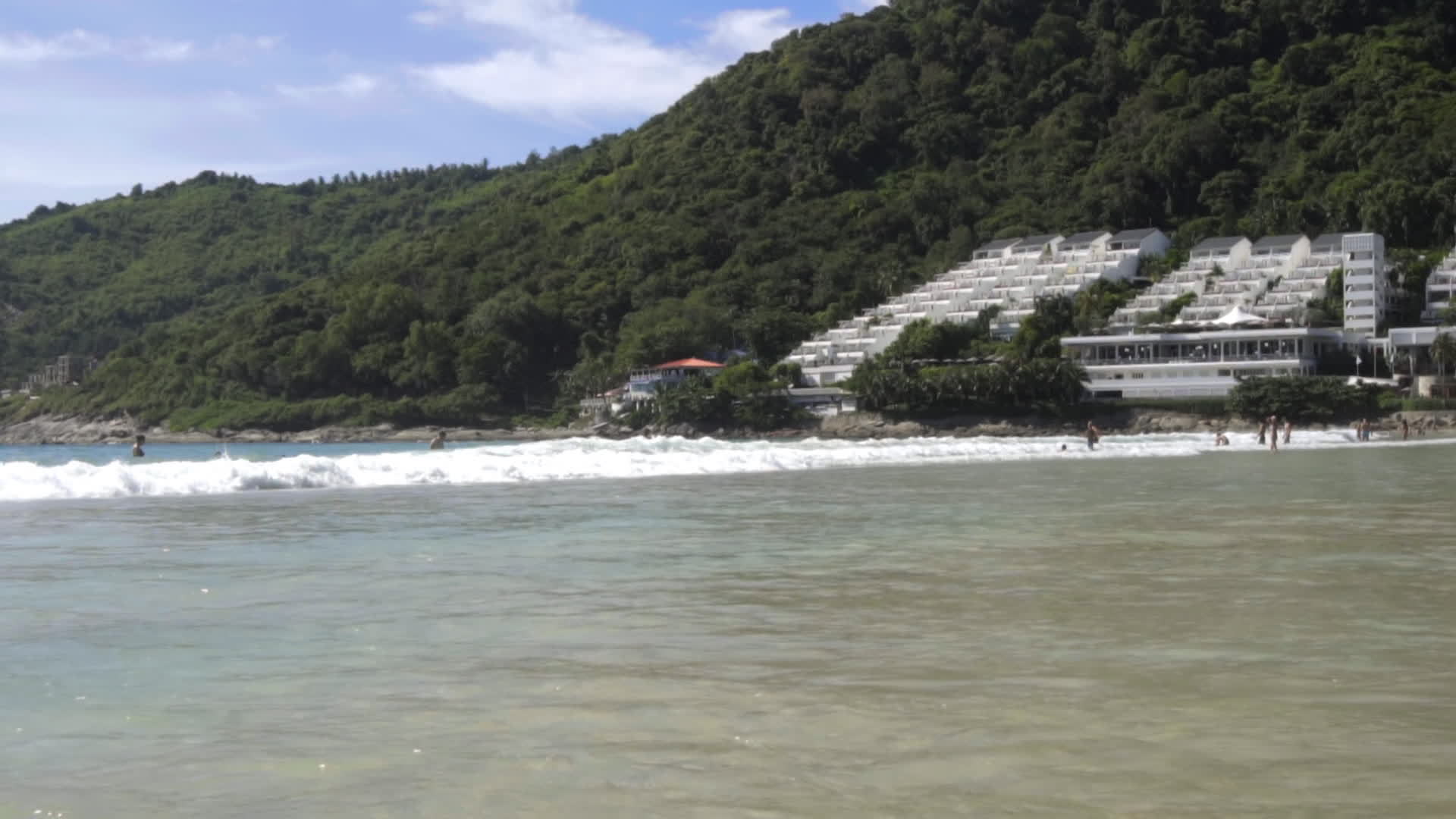 First person view, walk along the seashore. Waves roll on the beach. People swim away from the ...