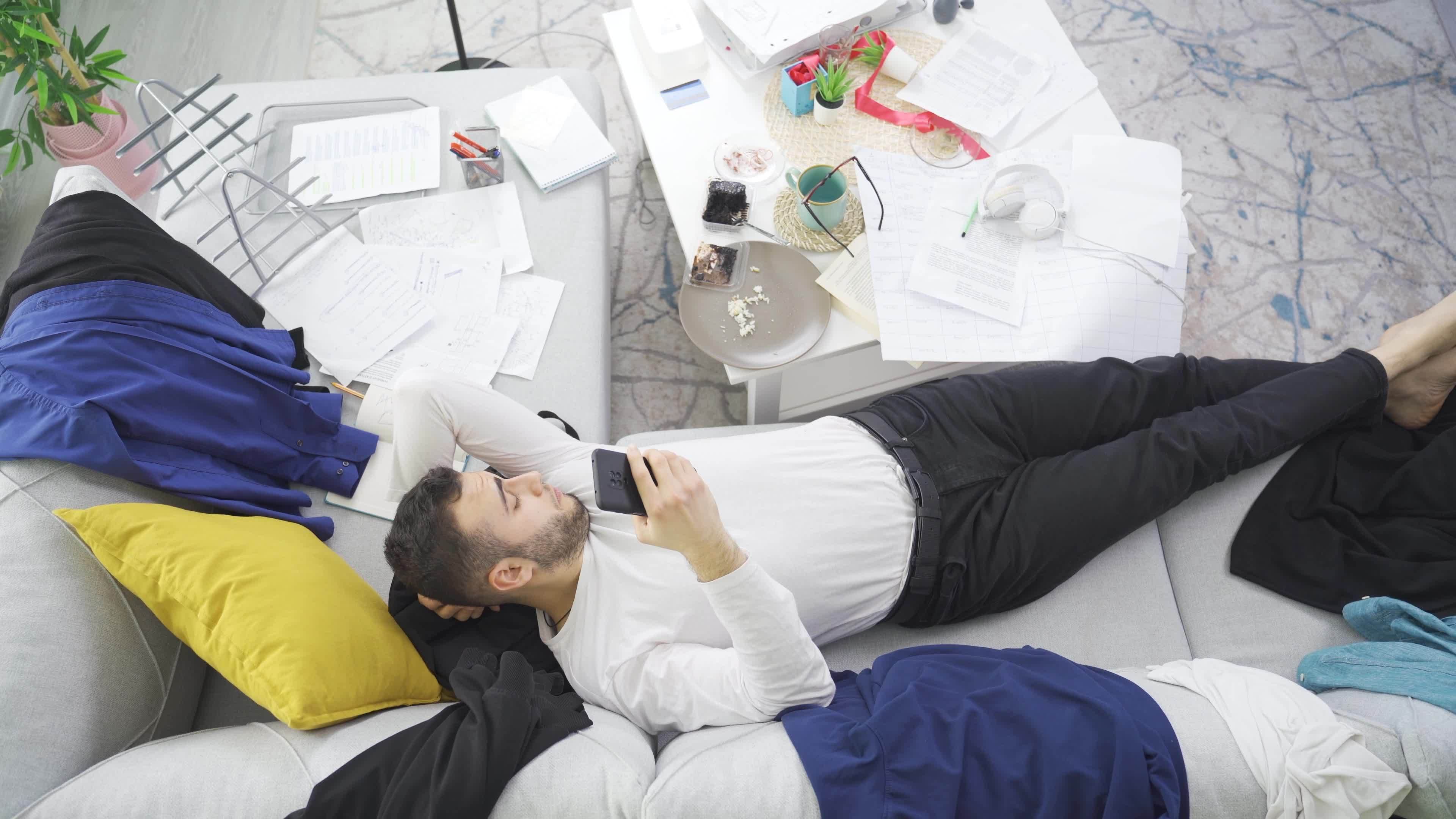 Tired lazy man lying on sofa in his untidy room. Messy and lazy man ...