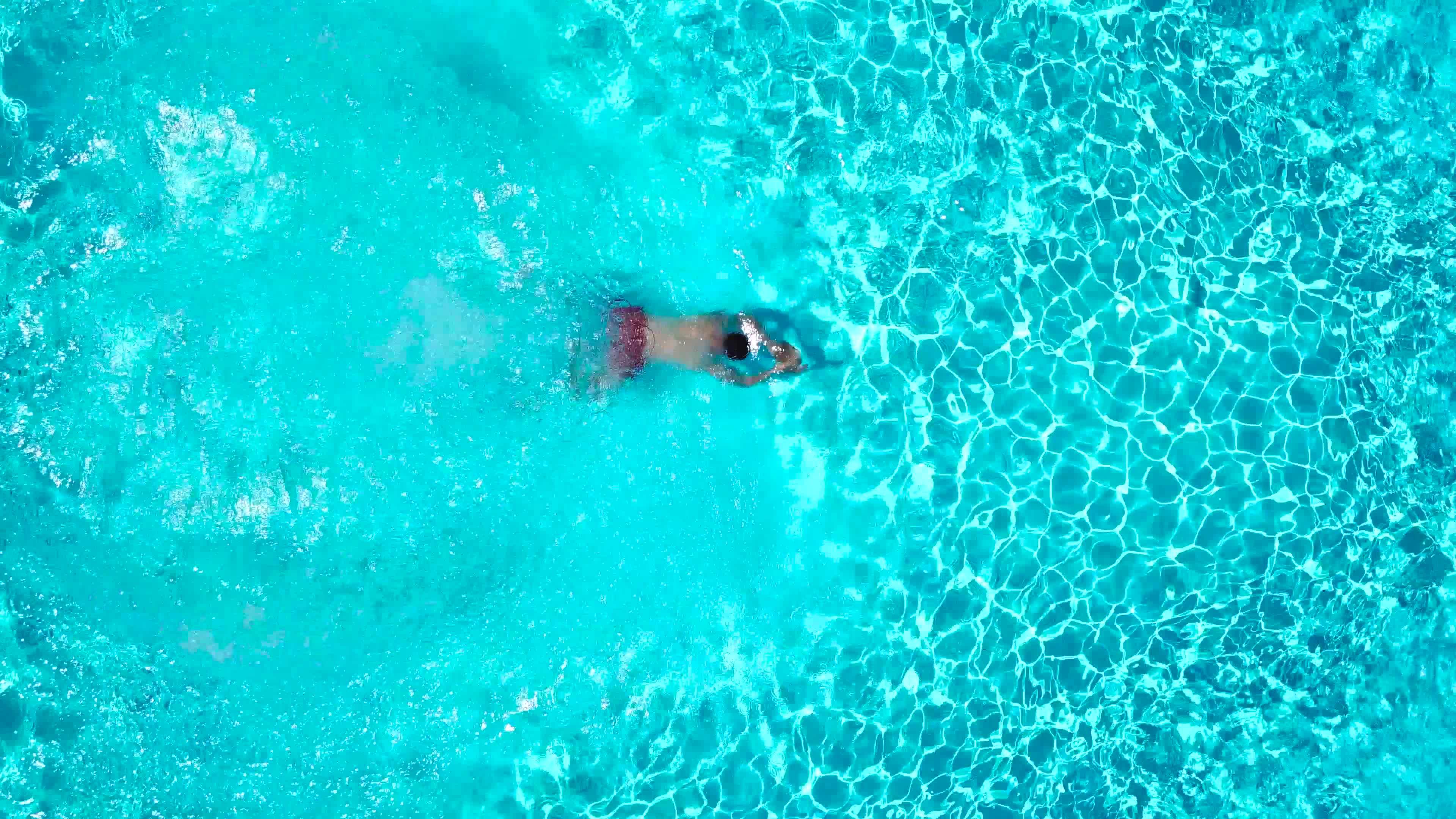 View From The Top As A Woman In A Blue Swimsuit Swims In The Pool Of A Hotel Villa Or Apartment