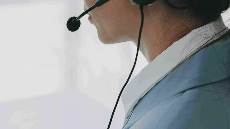 Call center agent with headset working on support hotline in modern office with copy space ...