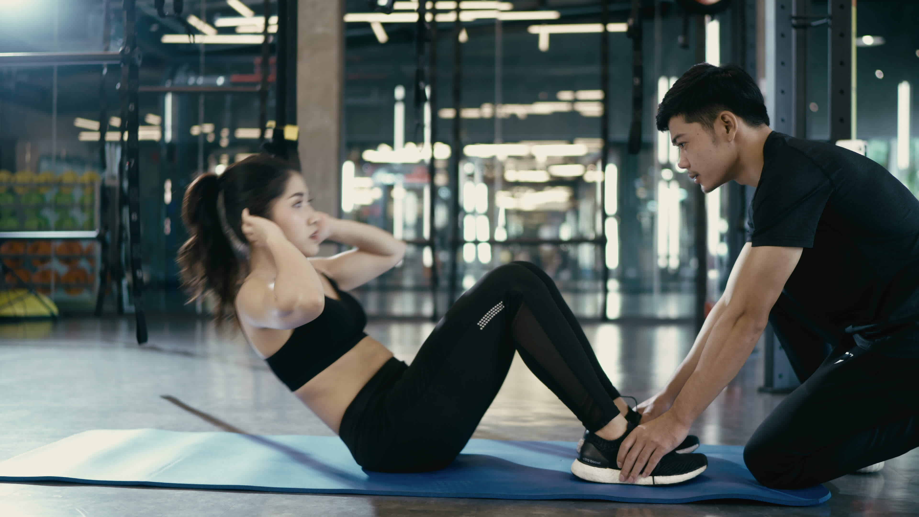 women wear sportswear does situps with personal trainer in the gym 23618520 Stock Video at Vecteezy