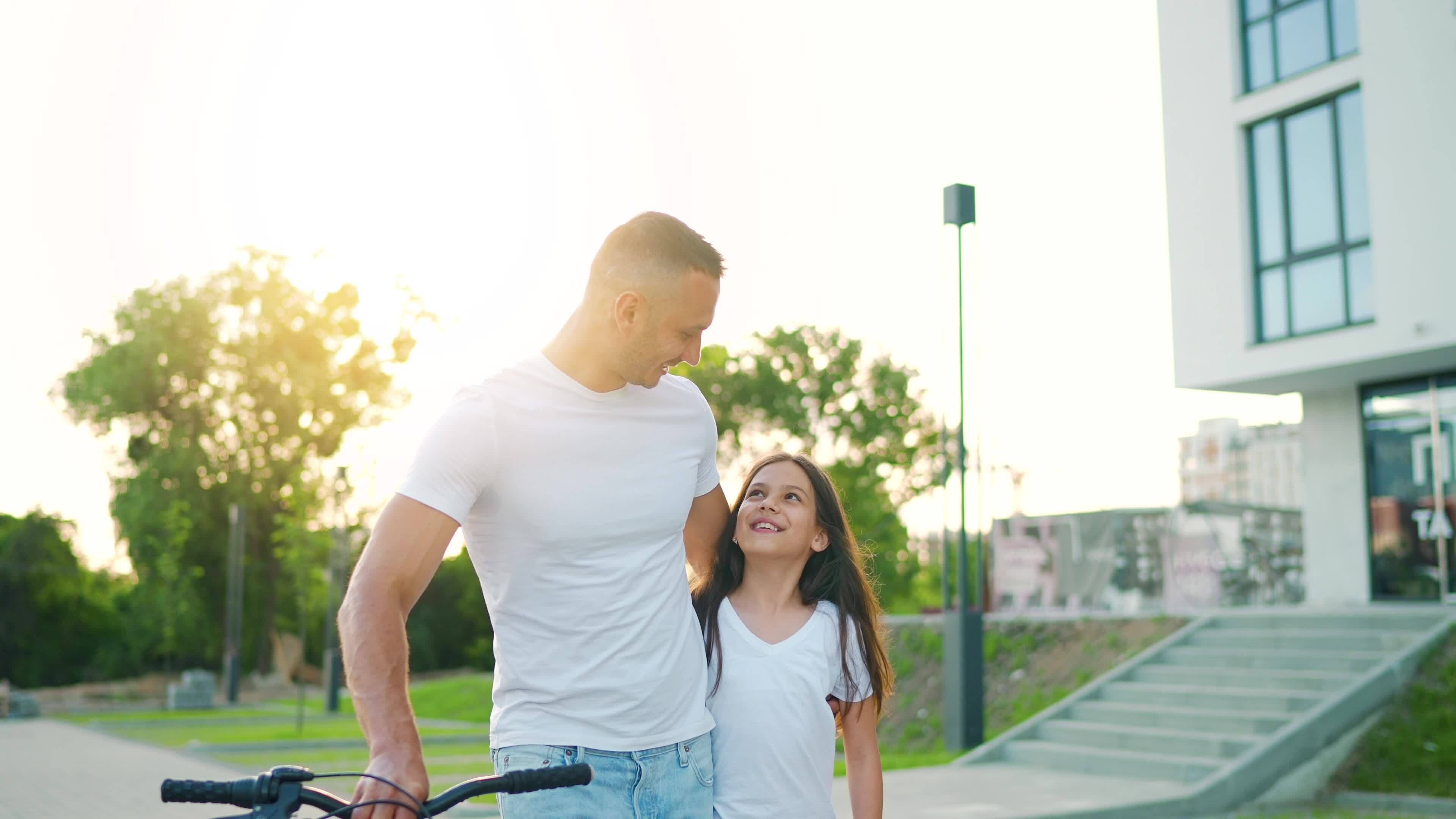 Dad is teaching daughter how to ride bicycle at sunset. Slow motion 24603098 Stock Video at Vecteezy