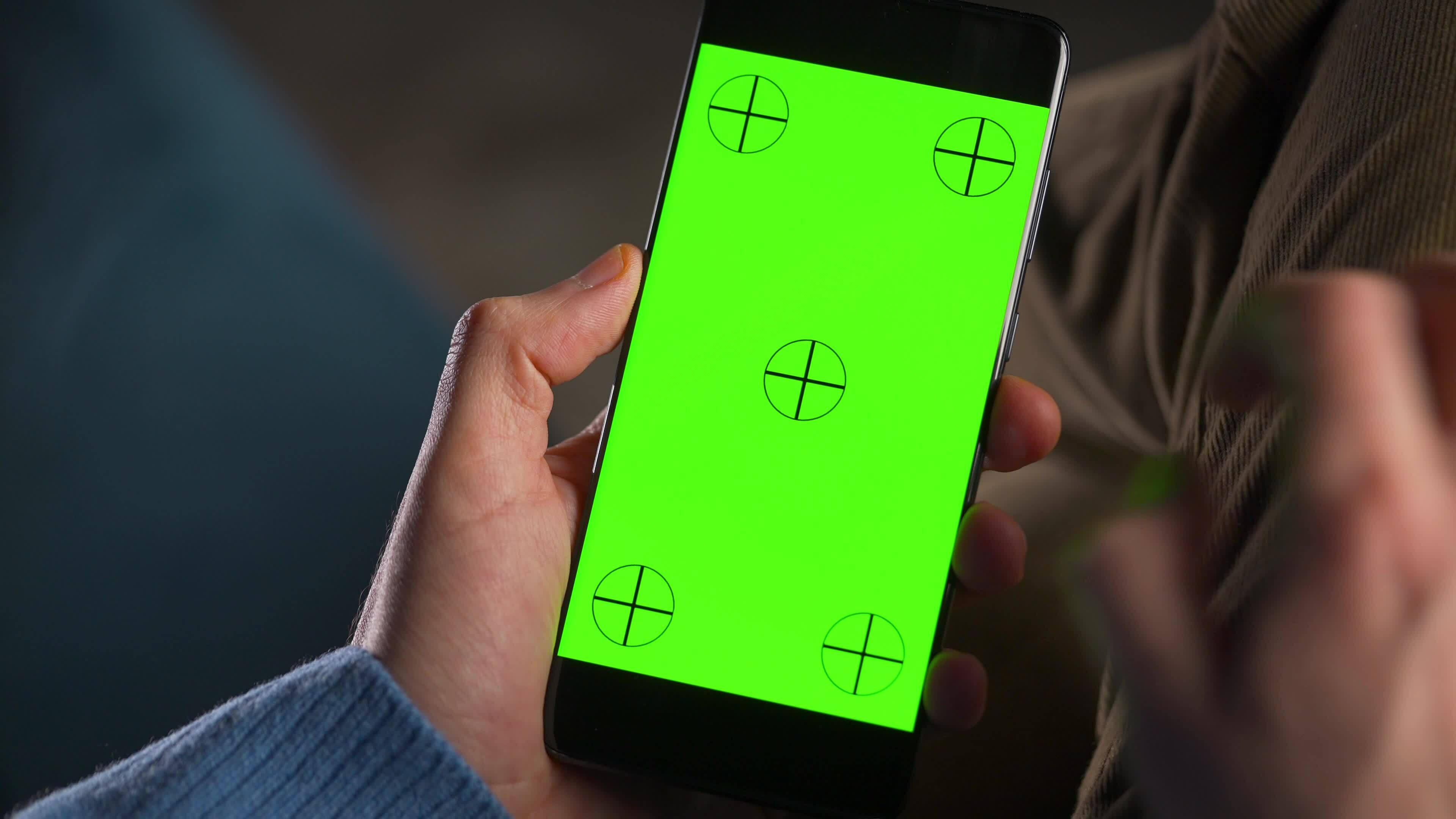 Man using smartphone with green mock-up screen in vertical mode and drinking coffee. Man ...