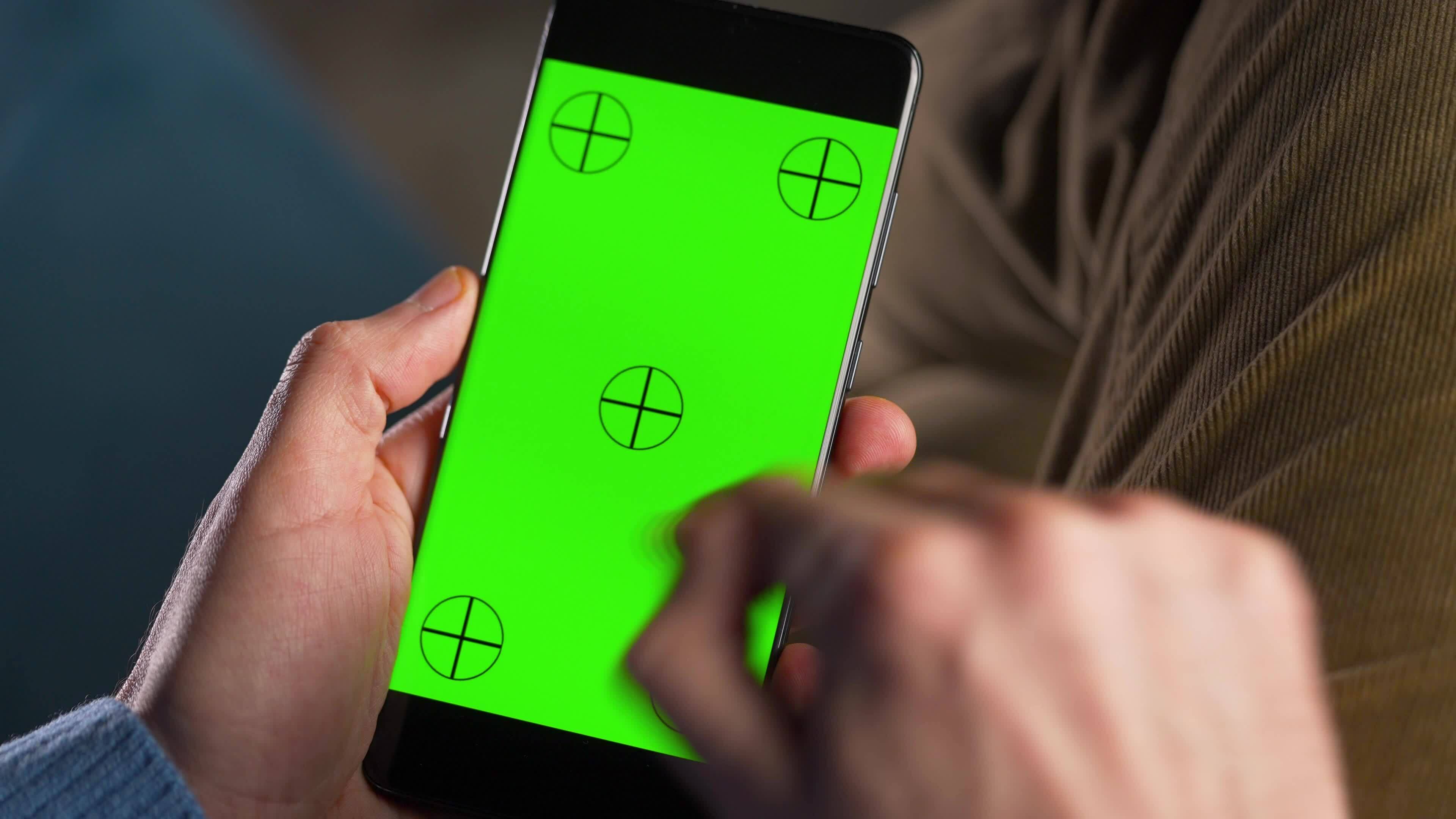 Man using smartphone with green mock-up screen in vertical mode and drinking coffee. Man ...
