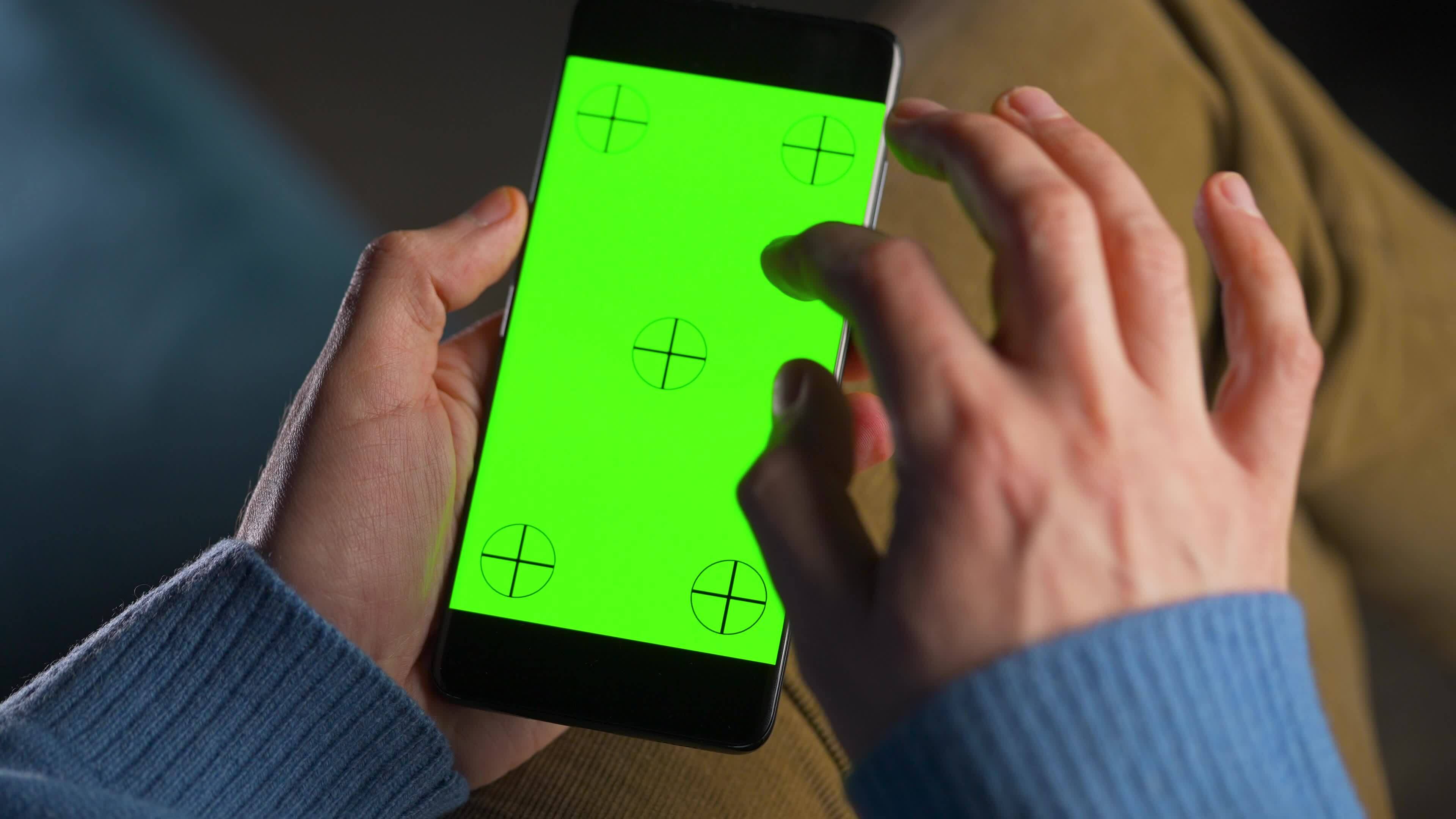 Man using smartphone with green mock-up screen in vertical mode and drinking coffee. Man ...