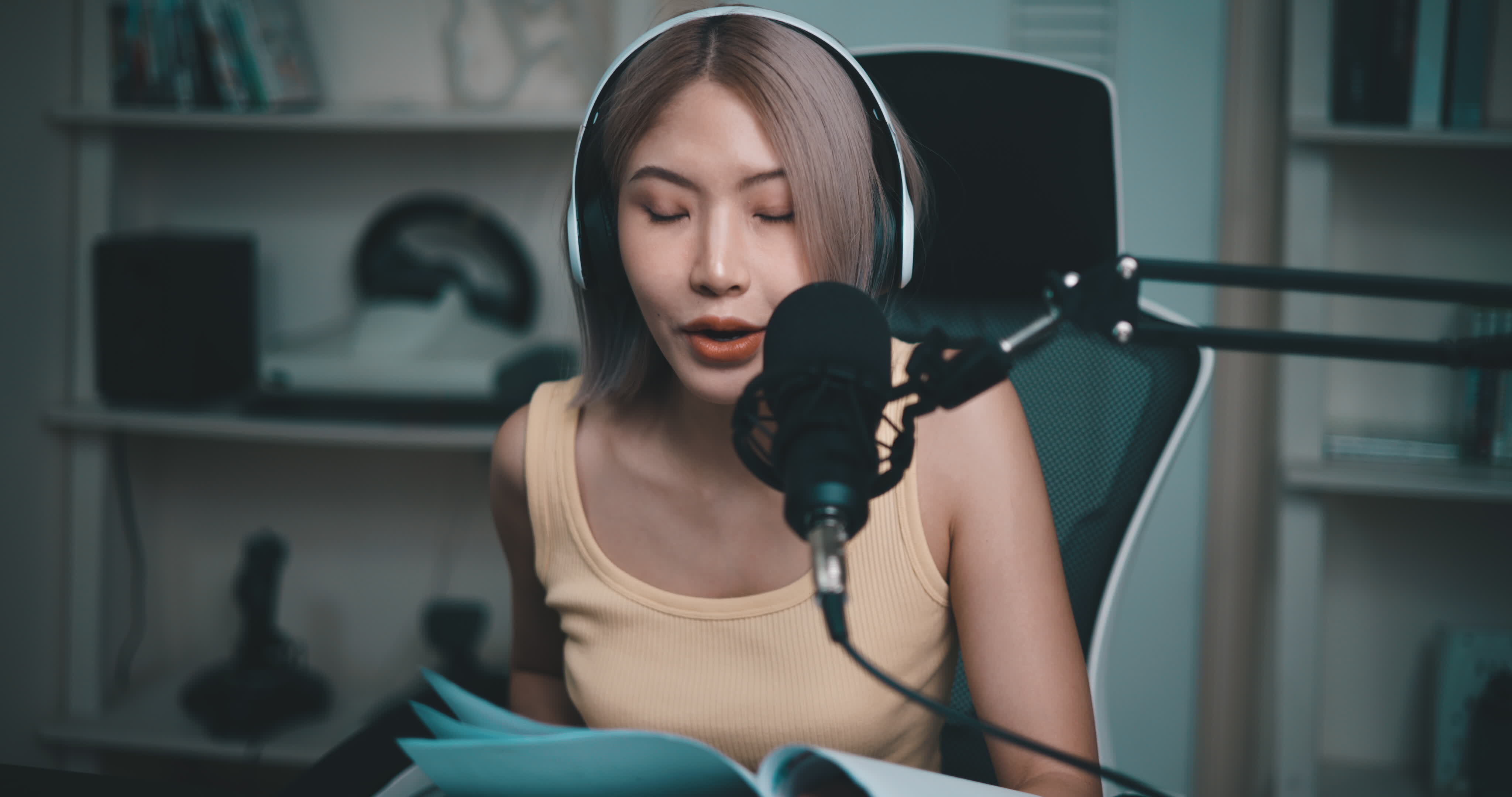 Footage of Young Asian woman influencer wearing headphones talking into a microphone while ...