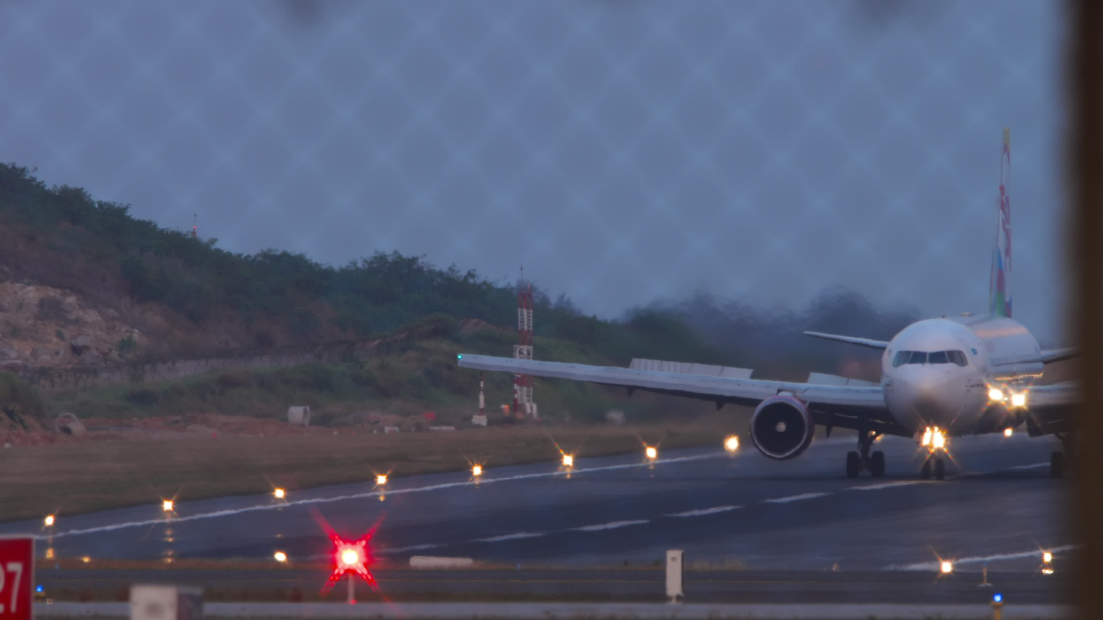 Shot, jet plane landing and braking. Airplane arriving. View through the fence. Runway lighting ...