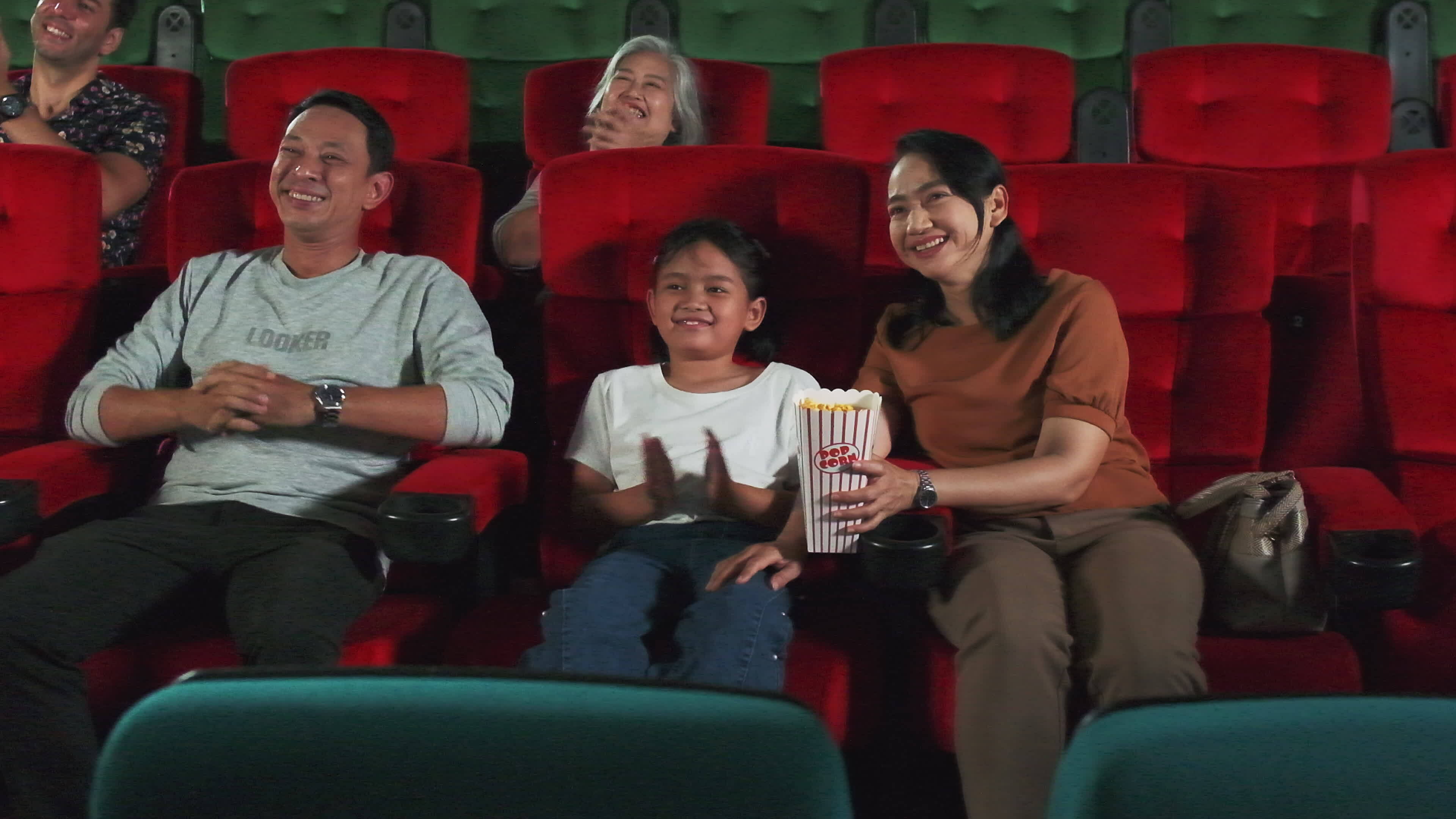 Various people in theater. Asian family, Kid, and parent audiences enjoy watching cinema and ...