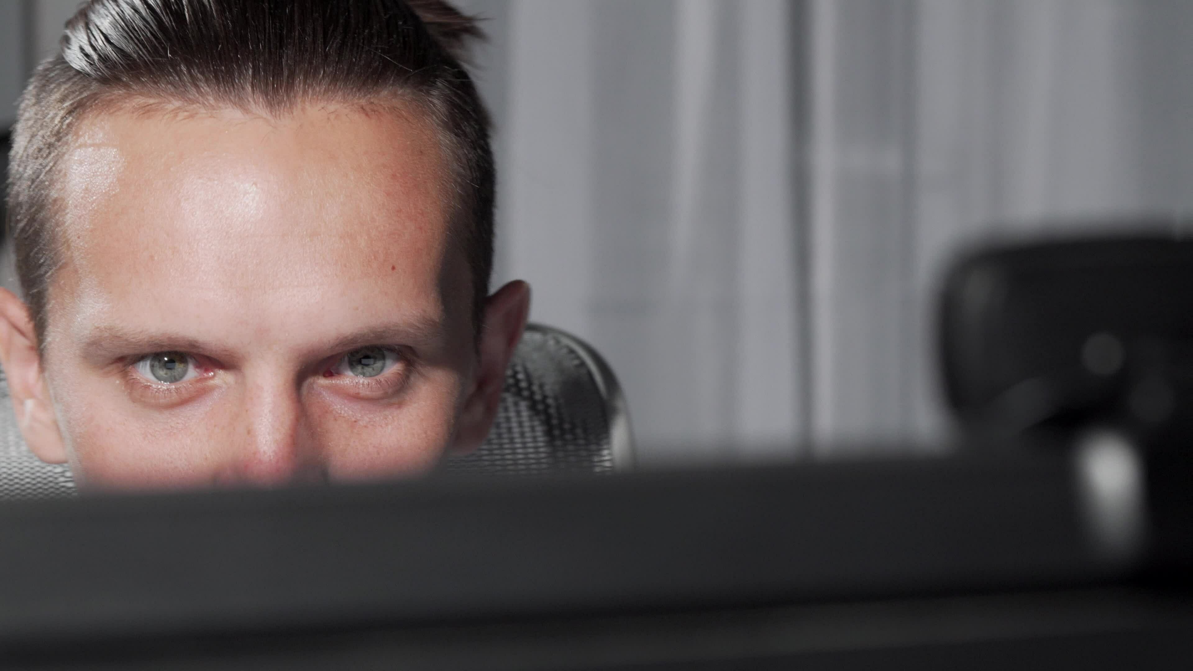 Sliding cropped shot of a male eyes looking at computer monitor ...