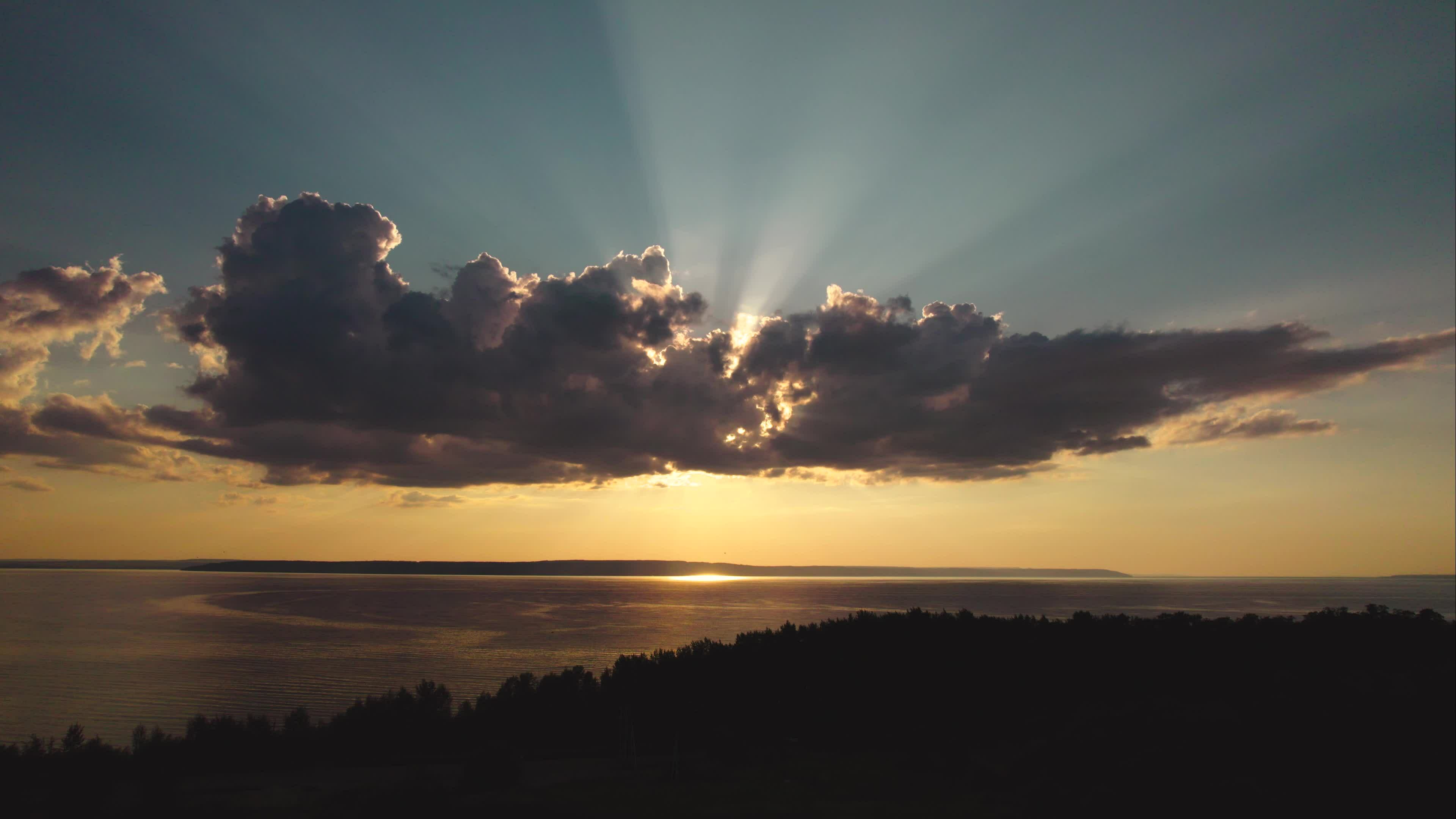 Gorgeous sunset scene over the river. The rays of the sun shine through the cloud. Warm colors ...