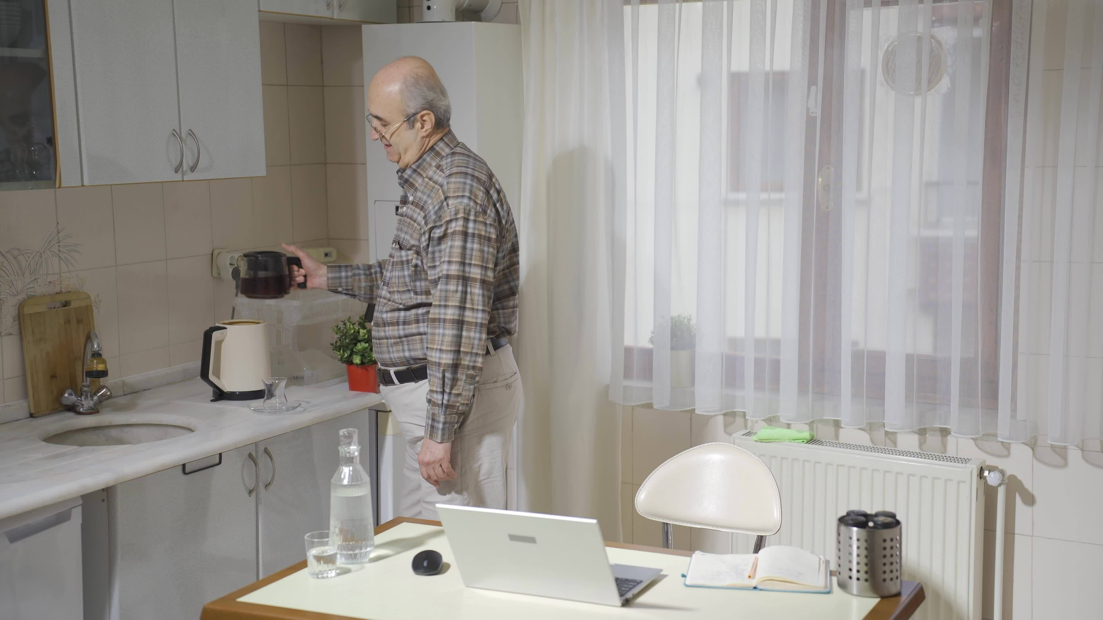 Happy old man using laptop in kitchen. 33546758 Stock Video at Vecteezy