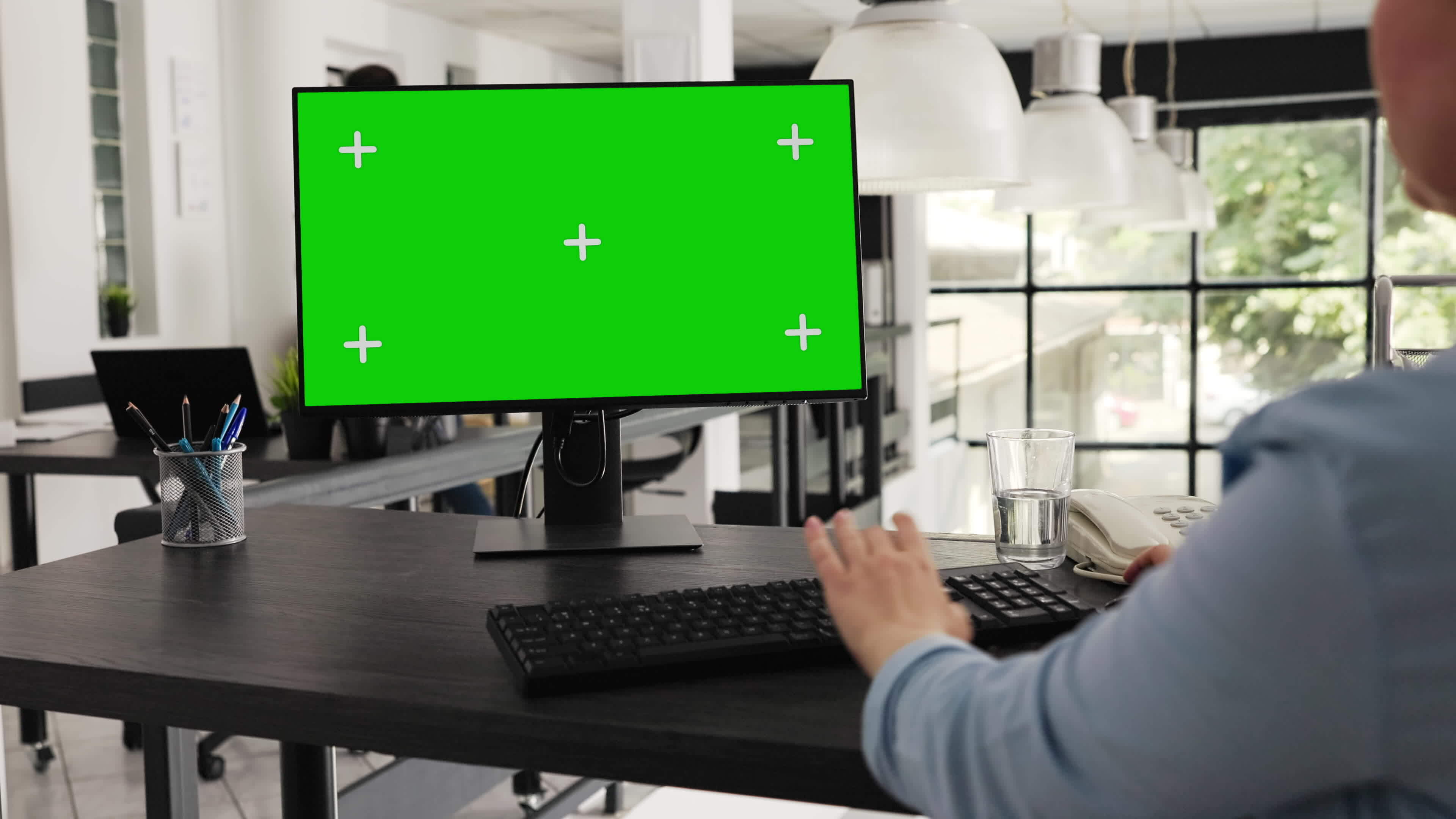 Employee Sitting At Desk With Greenscreen On Monitor Looking At