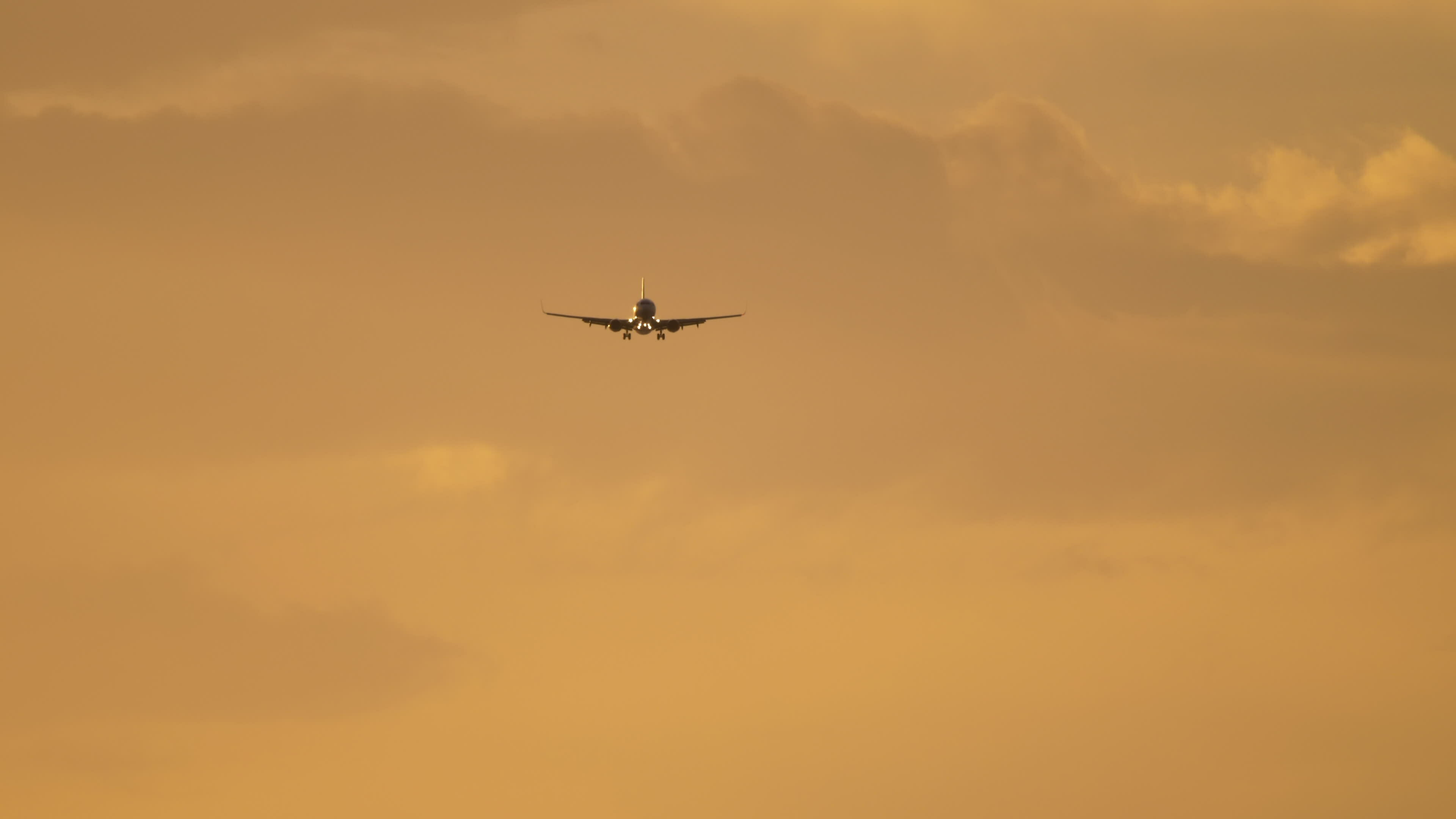 Jet Plane Approaching To Land At Bright Sunset Sky Unrecognizable