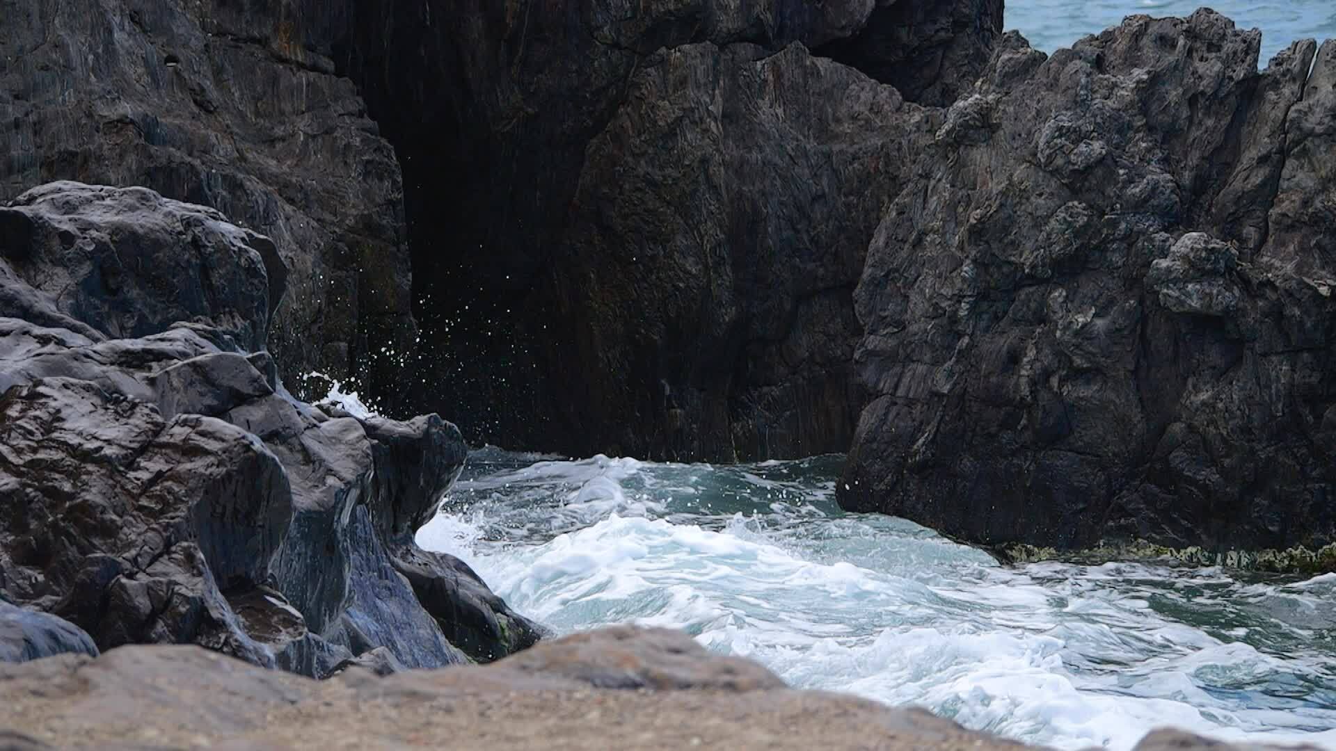 near the beach, sea waves wash over the rocks with big splashes, in ...